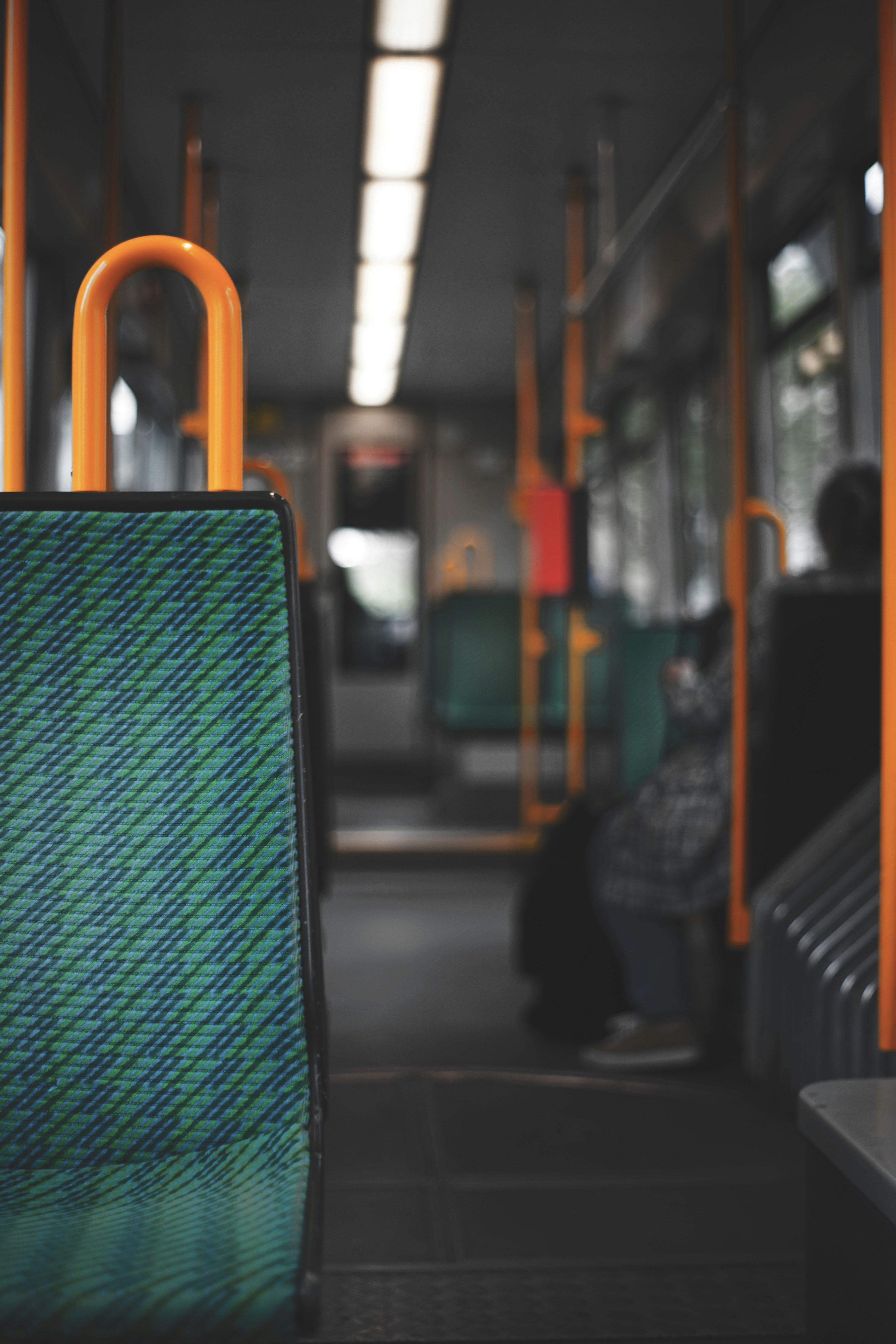 Interior of a public transport vehicle showcasing patterned seating and vibrant handrails, evoking a sense of daily commute. The scene captures the essence of urban life.
