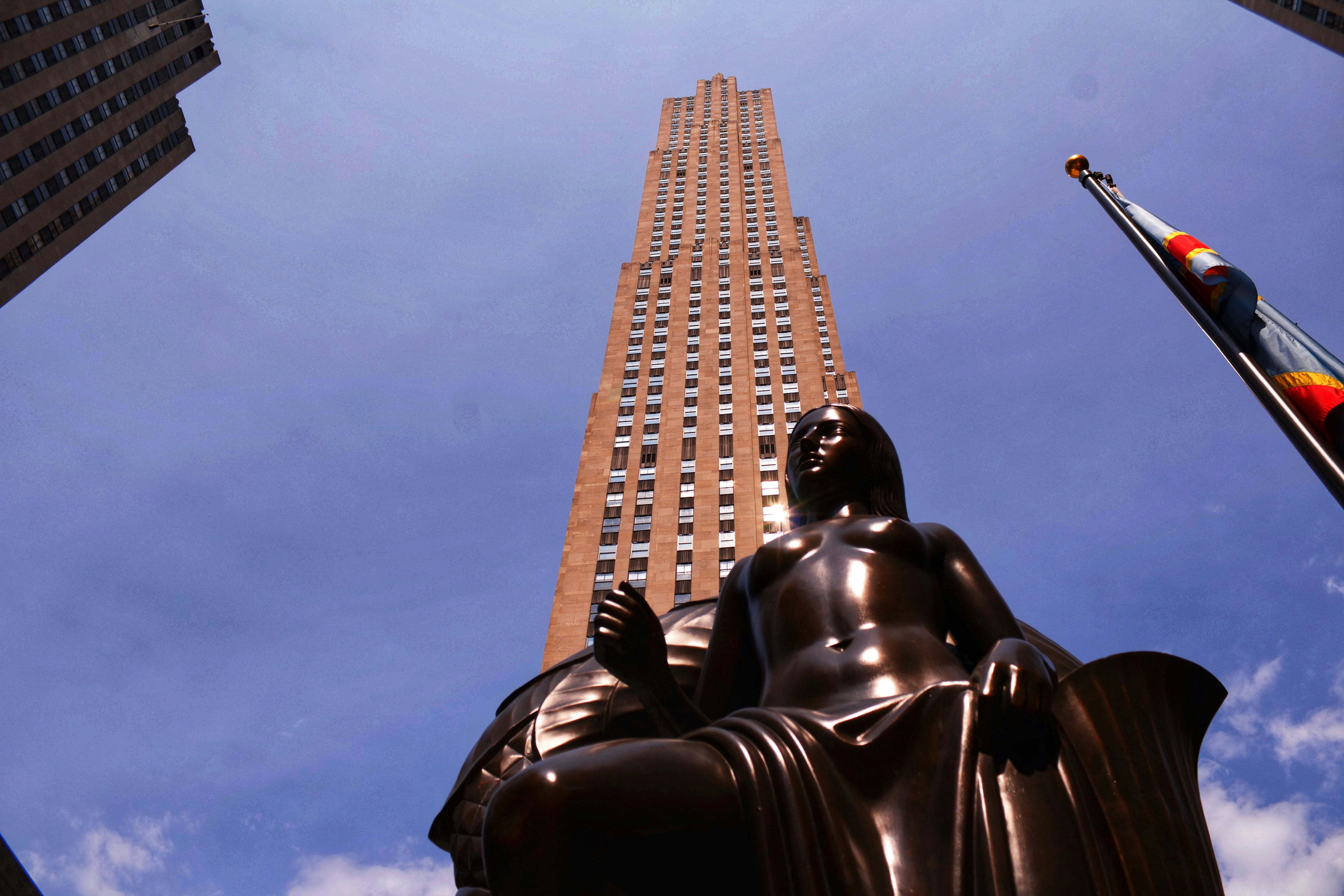 Bronze Giant Under a Vertical Sky: Statue Framed by a Skyscraper