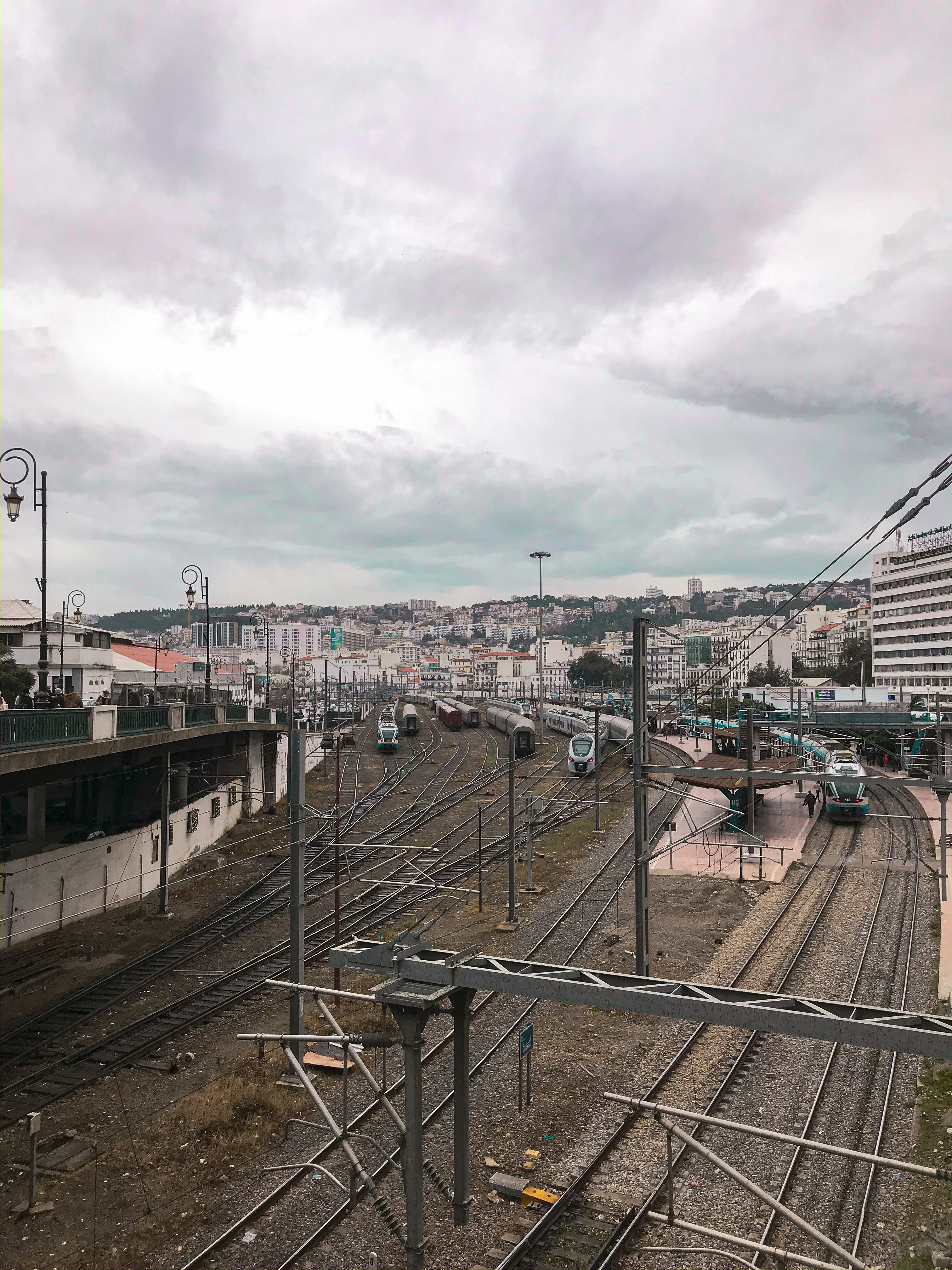 White and blue train on rail tracks under cloudy sky during daytime ...