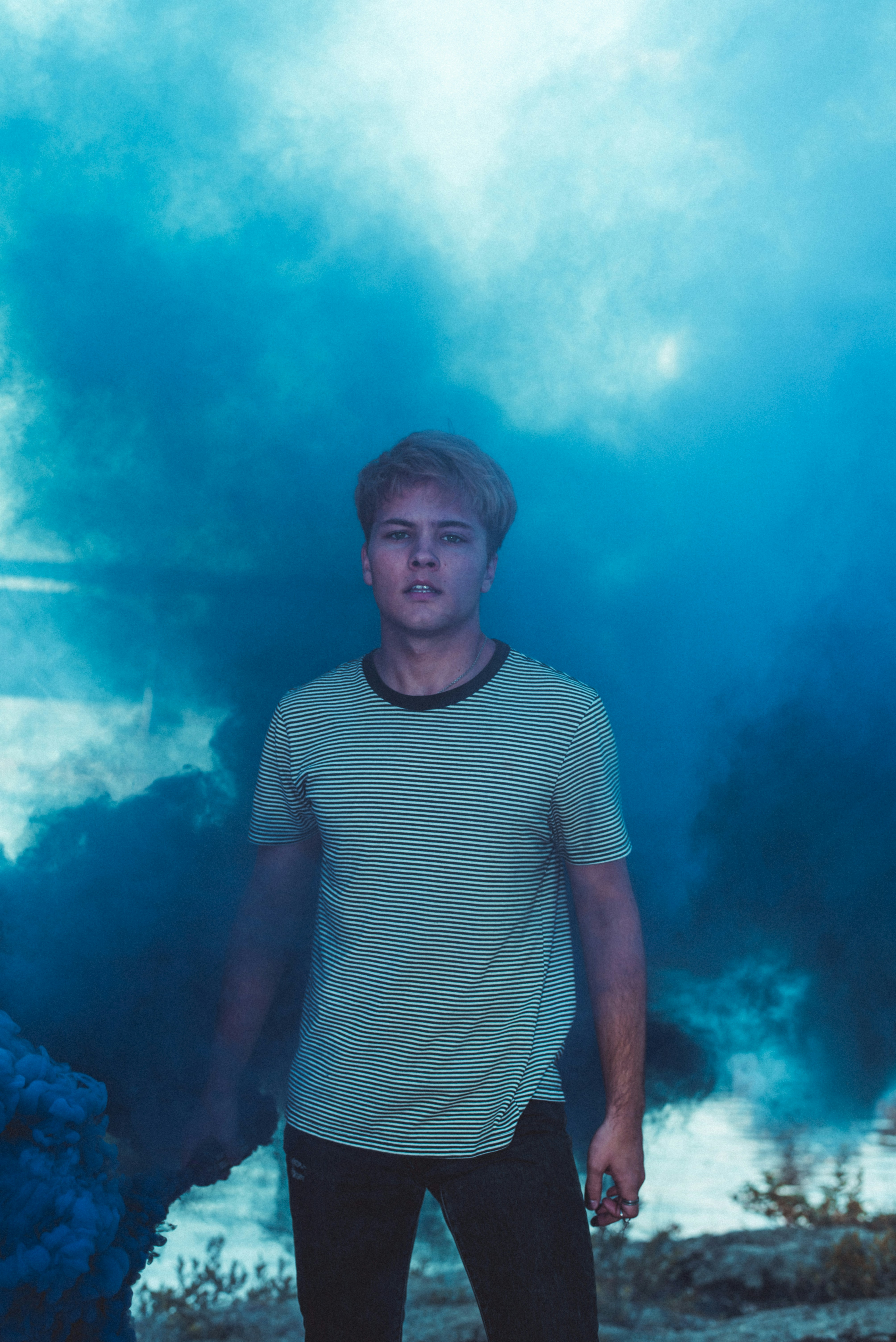 Blue Veil Portrait: A Youth Emerges from Cyan Smoke