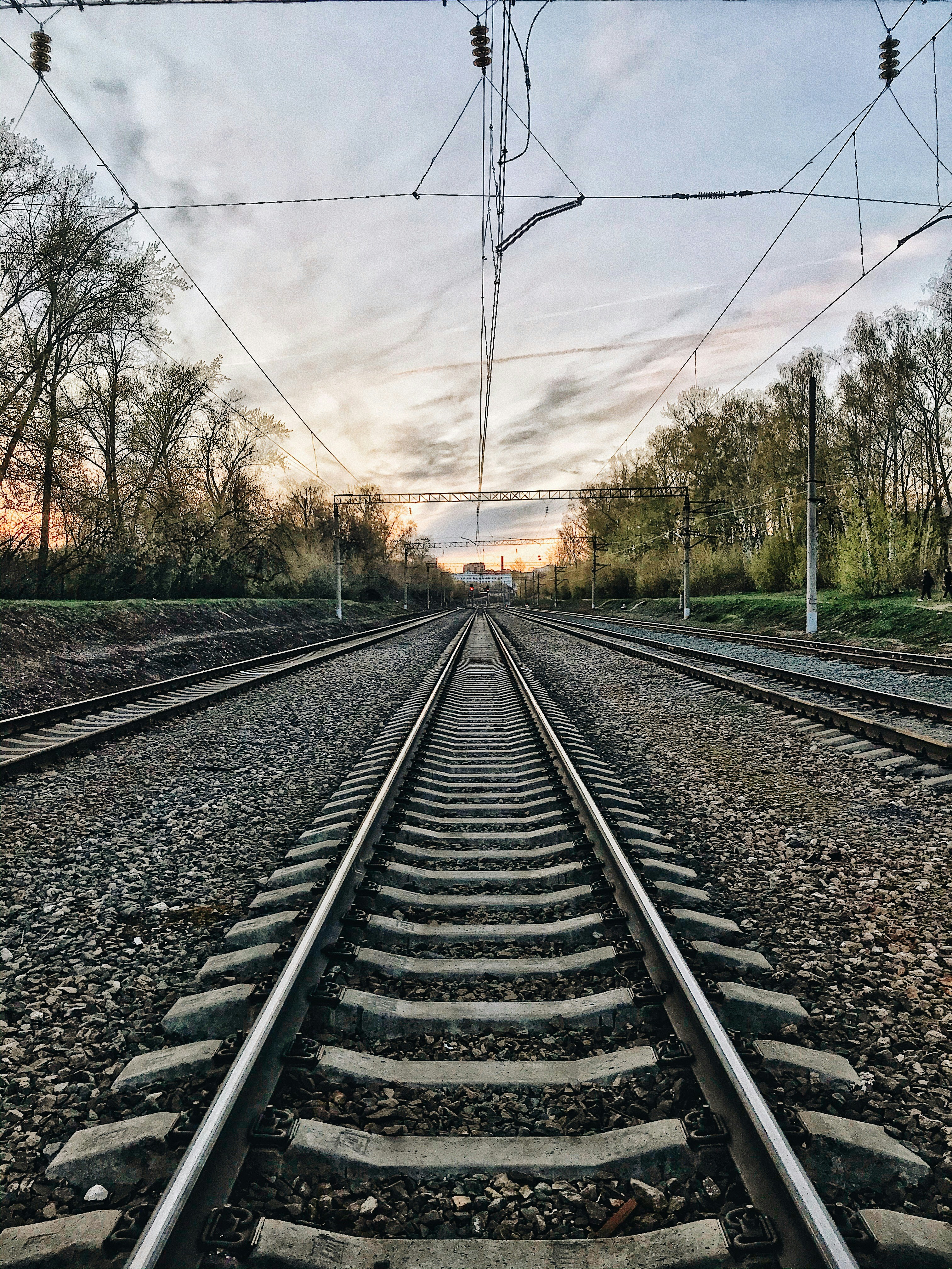black metal train rail near trees during daytime