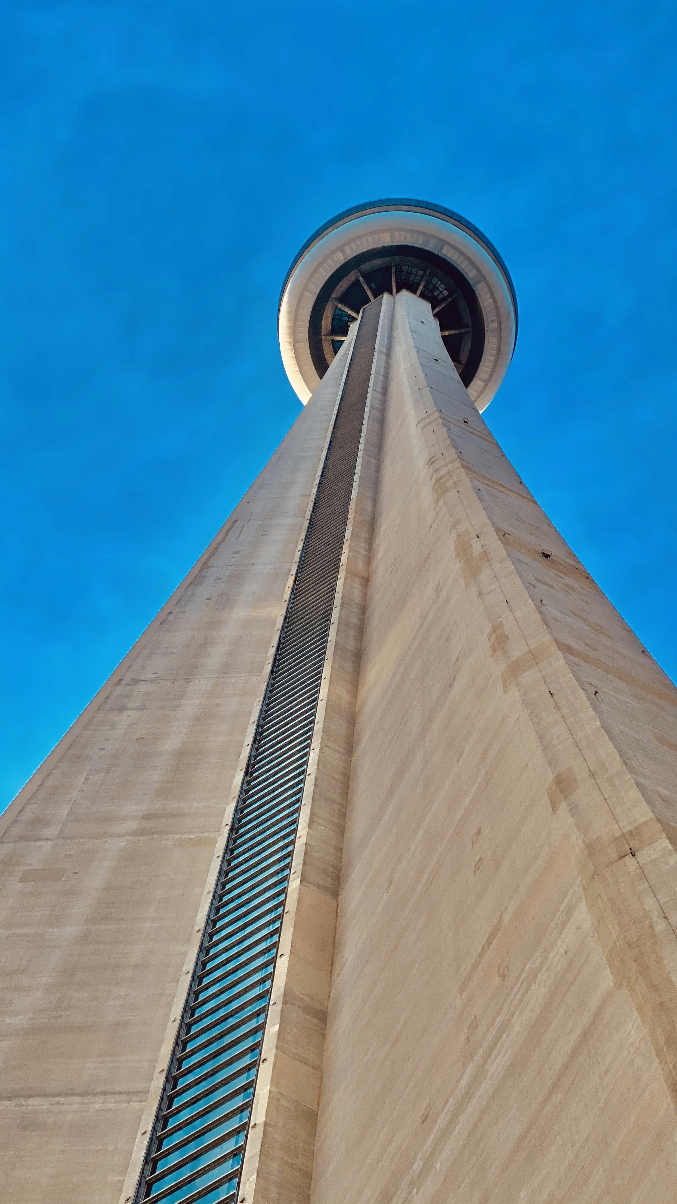 The CN Tower rises majestically against a clear blue sky, showcasing its sleek architectural lines and observation deck.
