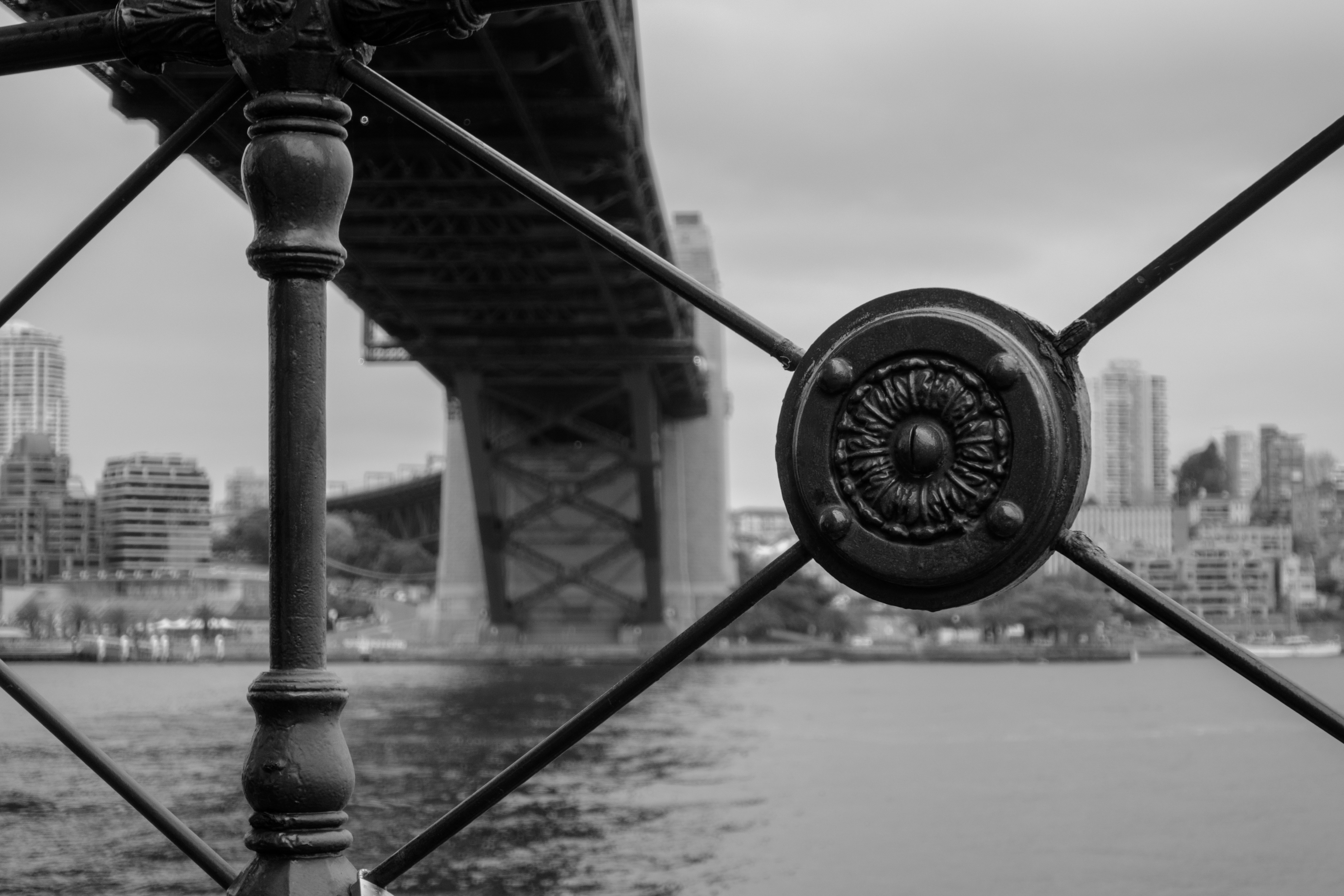 Rosette in Steel: Close-Up of a Bridge Lattice with an Urban Backdrop