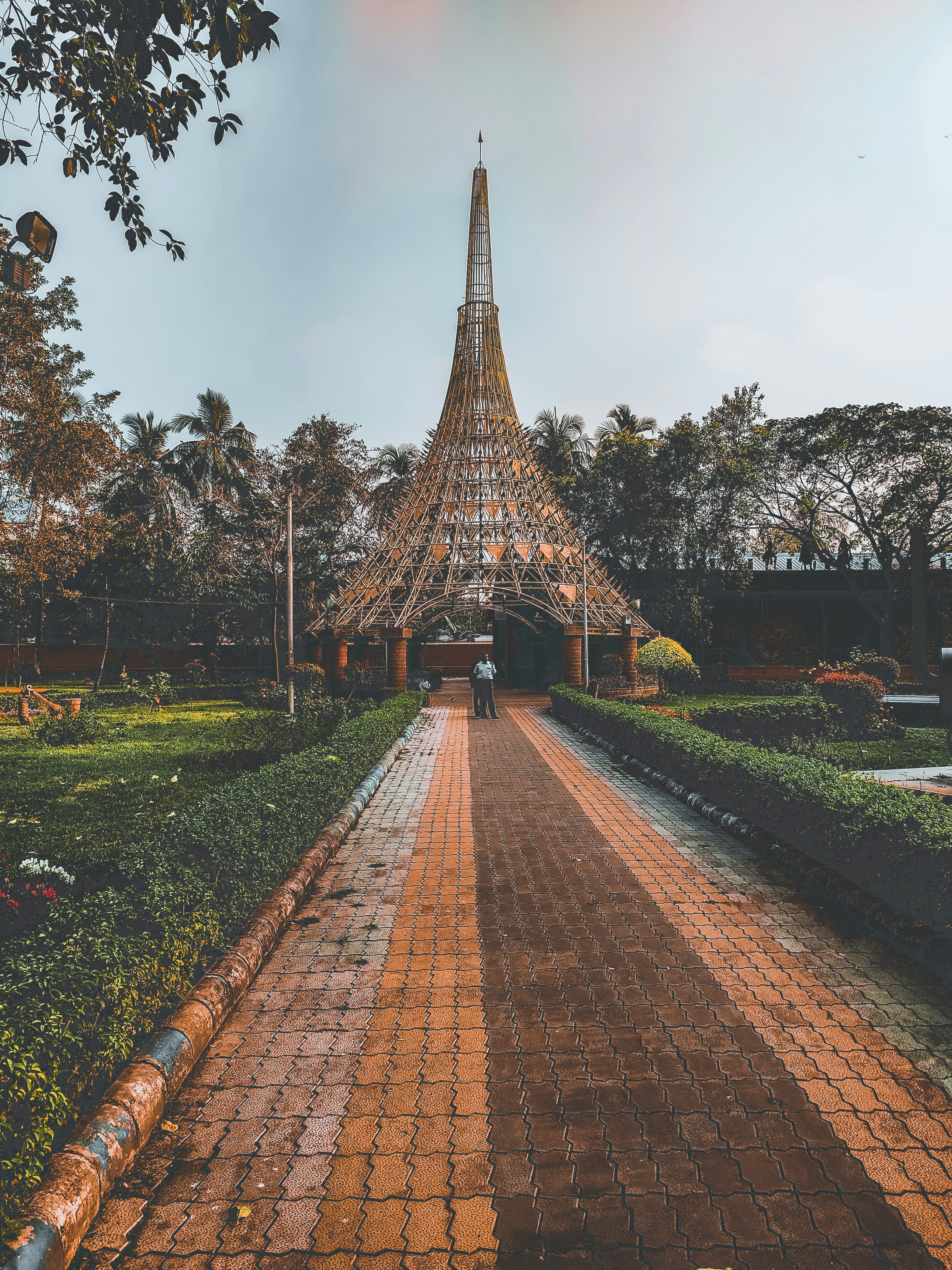 A unique architectural structure framed by lush greenery and a winding pathway, inviting visitors to explore its beauty.
