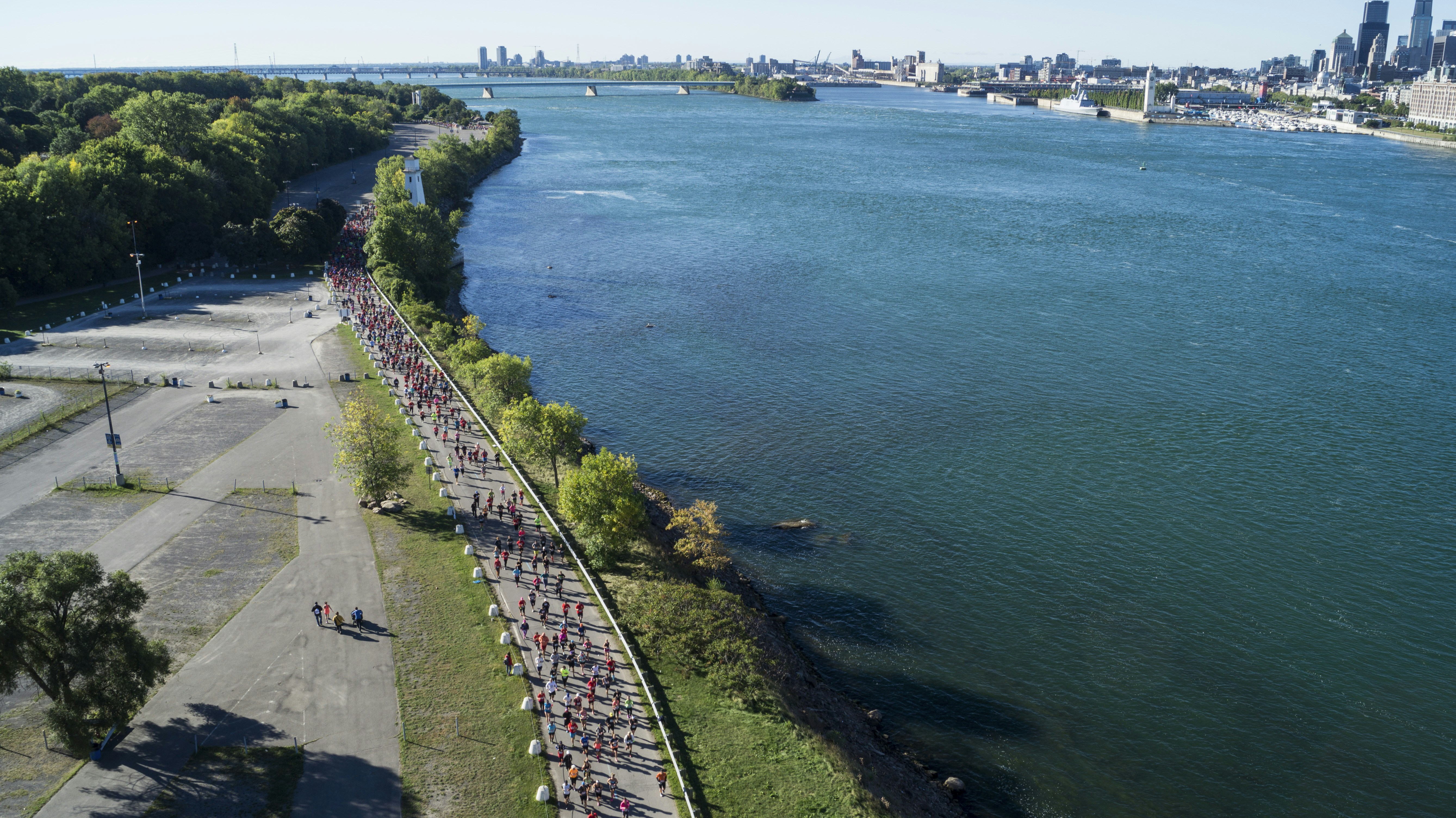 People Run Along the Riverside Causeway Under a Blue Sky