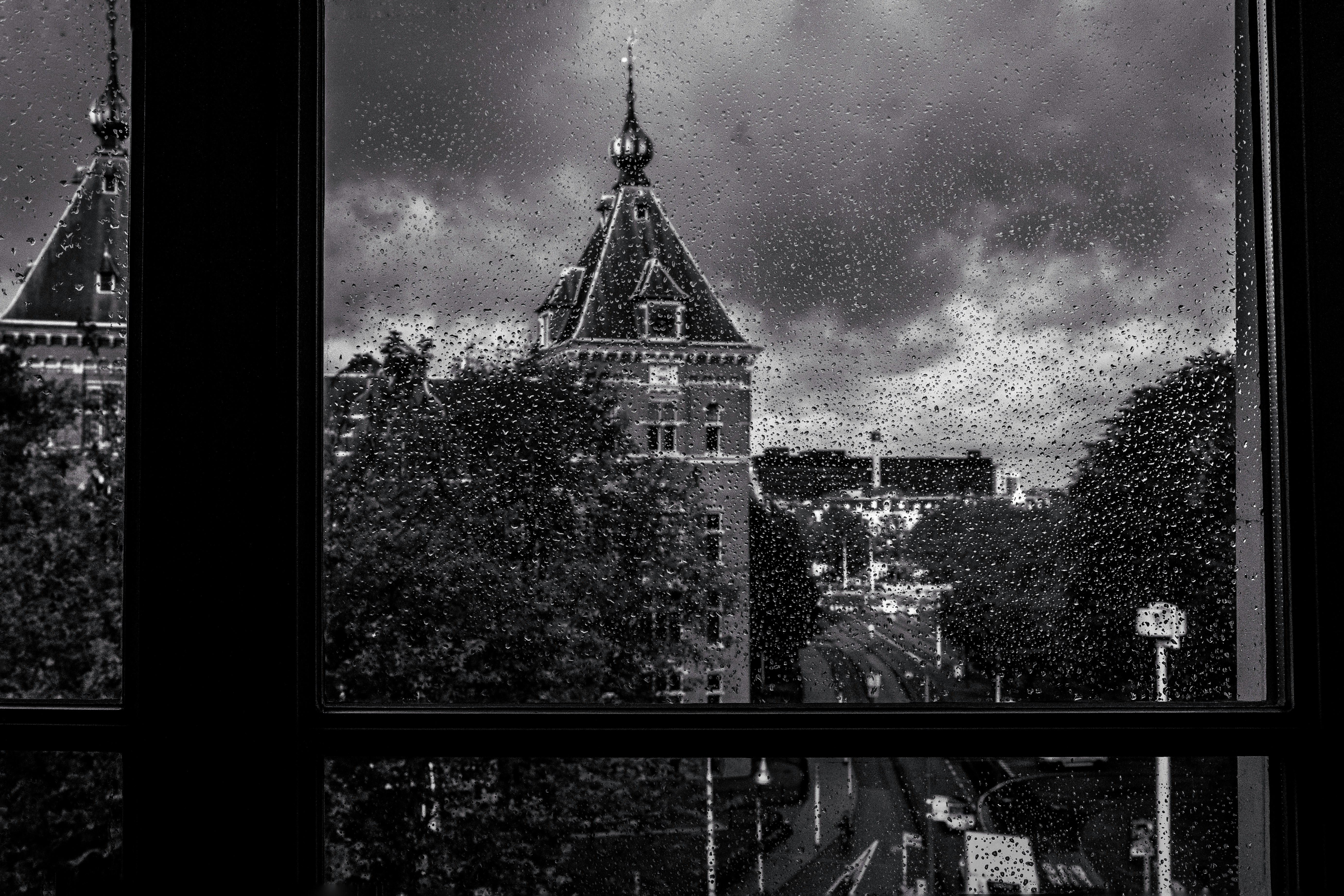 Rain-Kissed Window Frames a Gothic Spire Against Stormy Night Skies