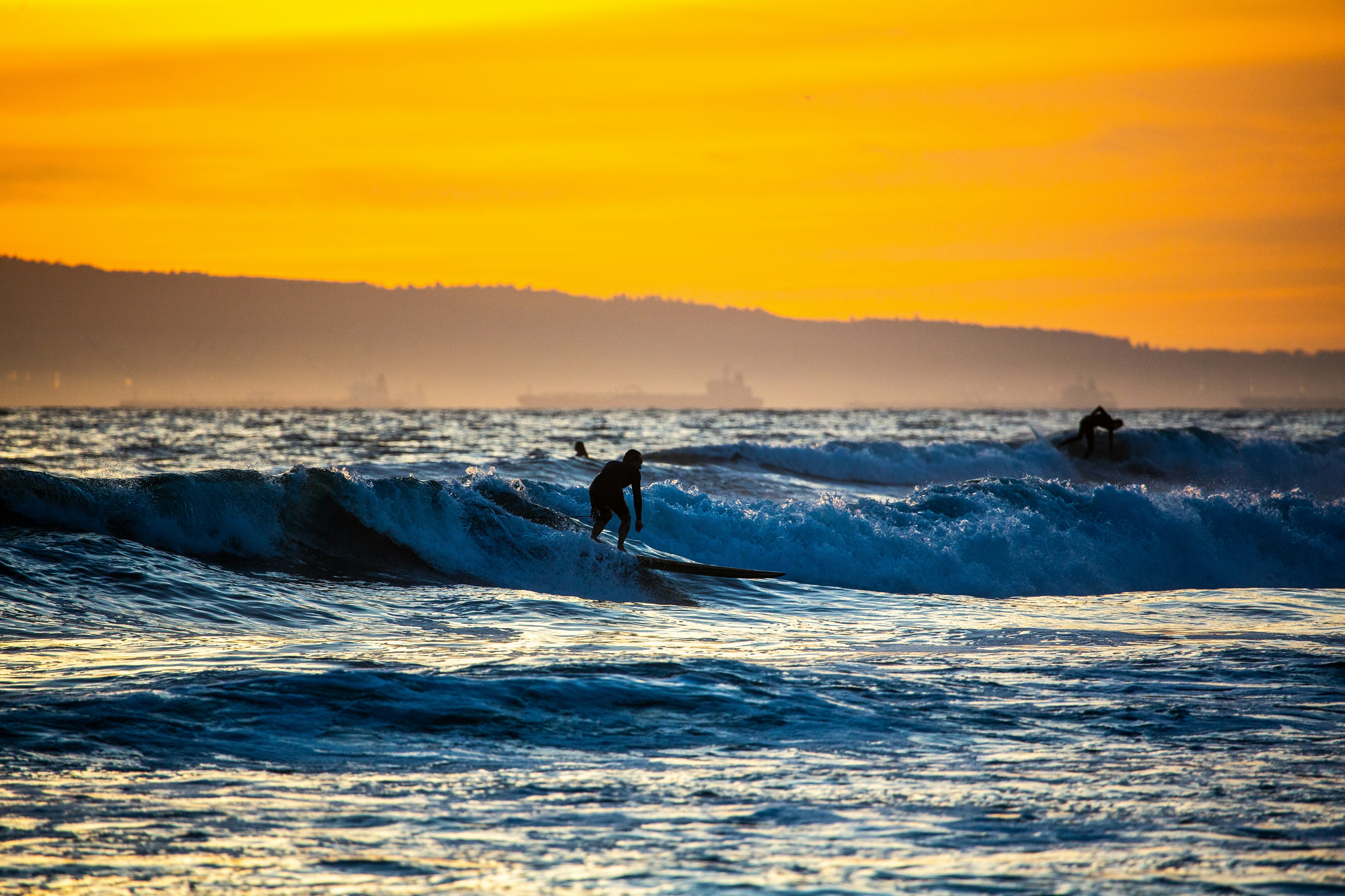Silueta de 2 personas surfeando en las olas del mar durante la puesta del sol foto – Imagen de ...