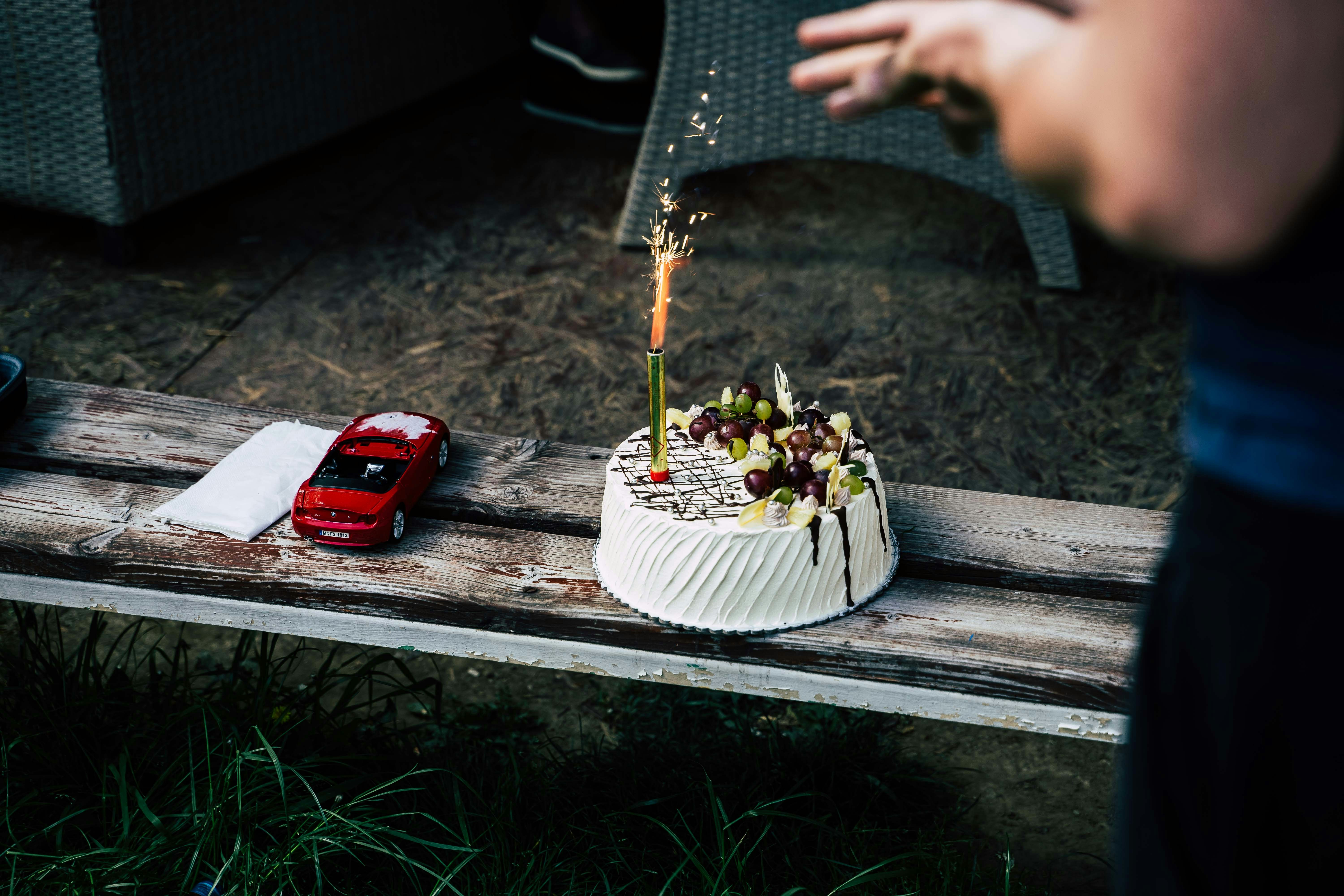 a cake on a wooden table with a red car in the background