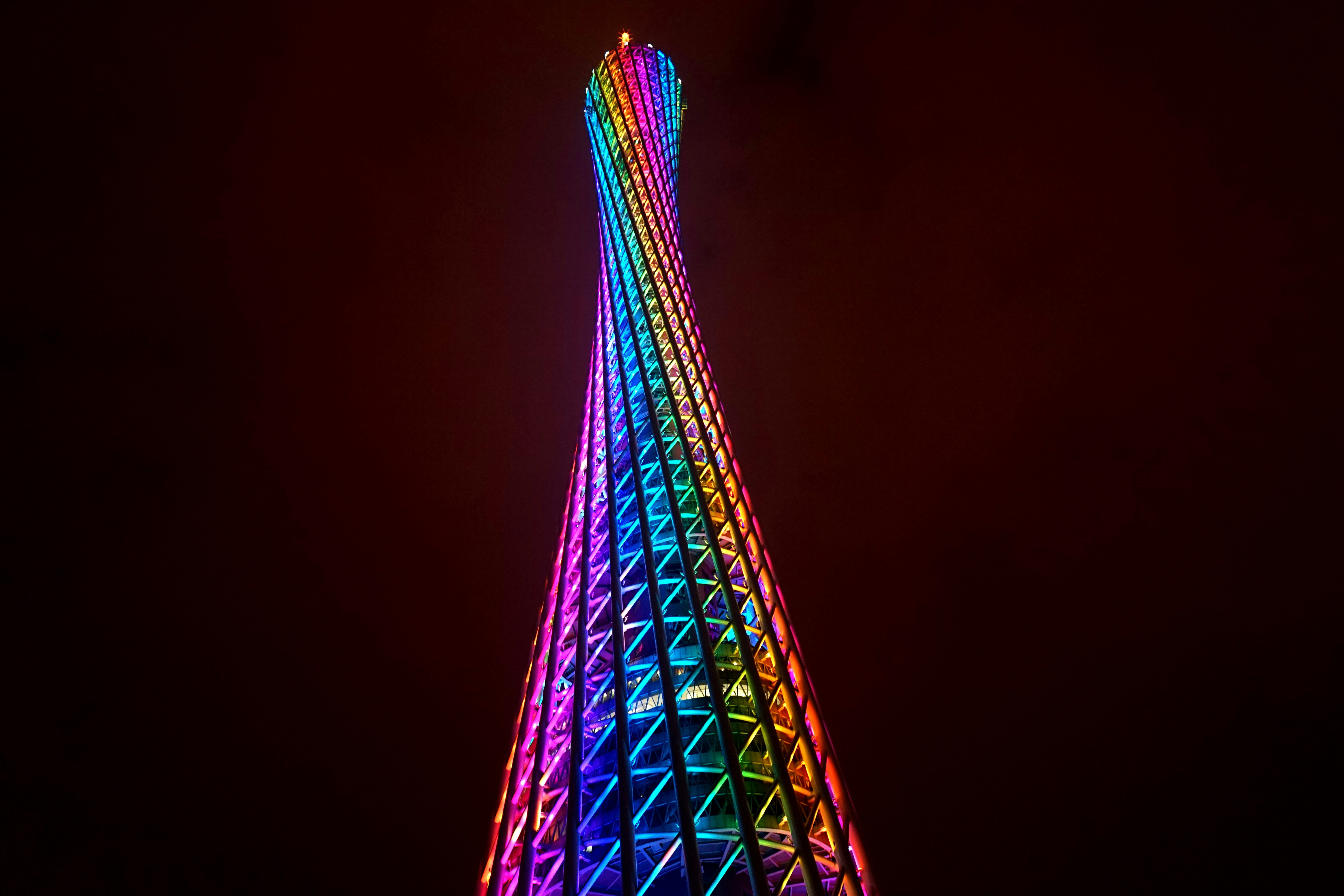 Colorfully lit tower spiraling into the dark sky, showcasing a vivid spectrum of hues.