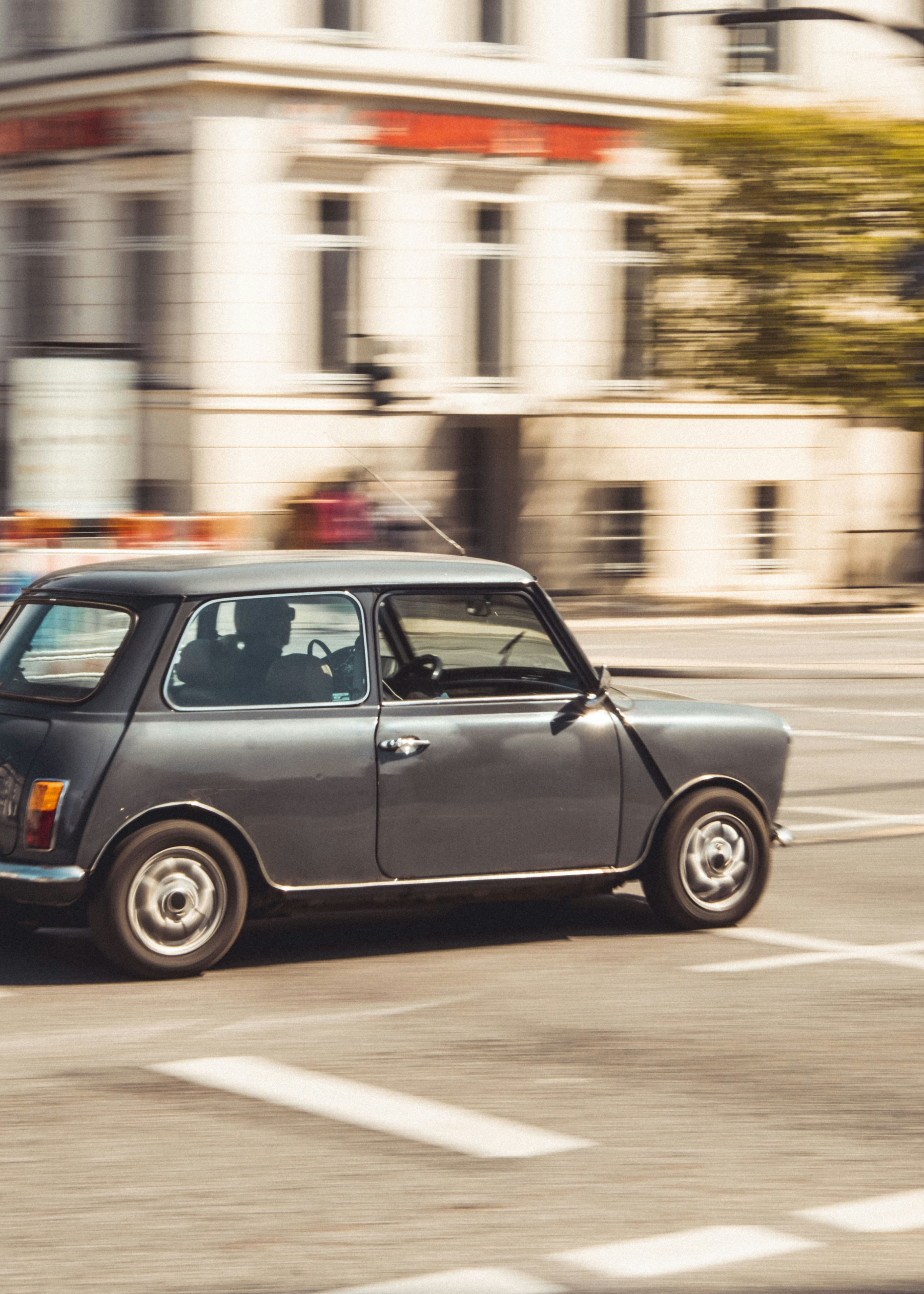 Classic Mini Cooper navigating a city intersection, showcasing its iconic design and urban spirit.
