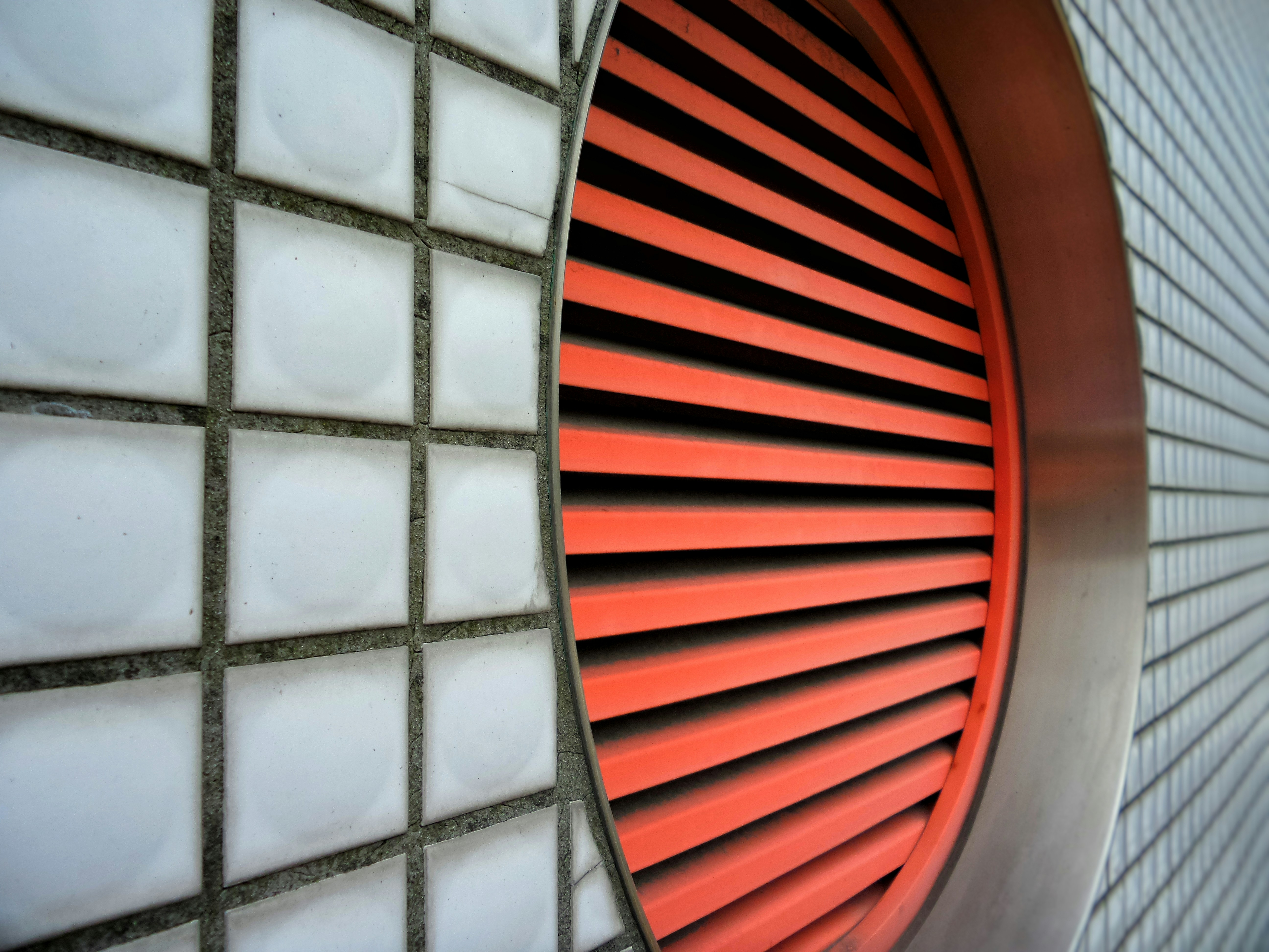 Crimson Circle: Close-Up on a Red Vent Framed by Tile Grid