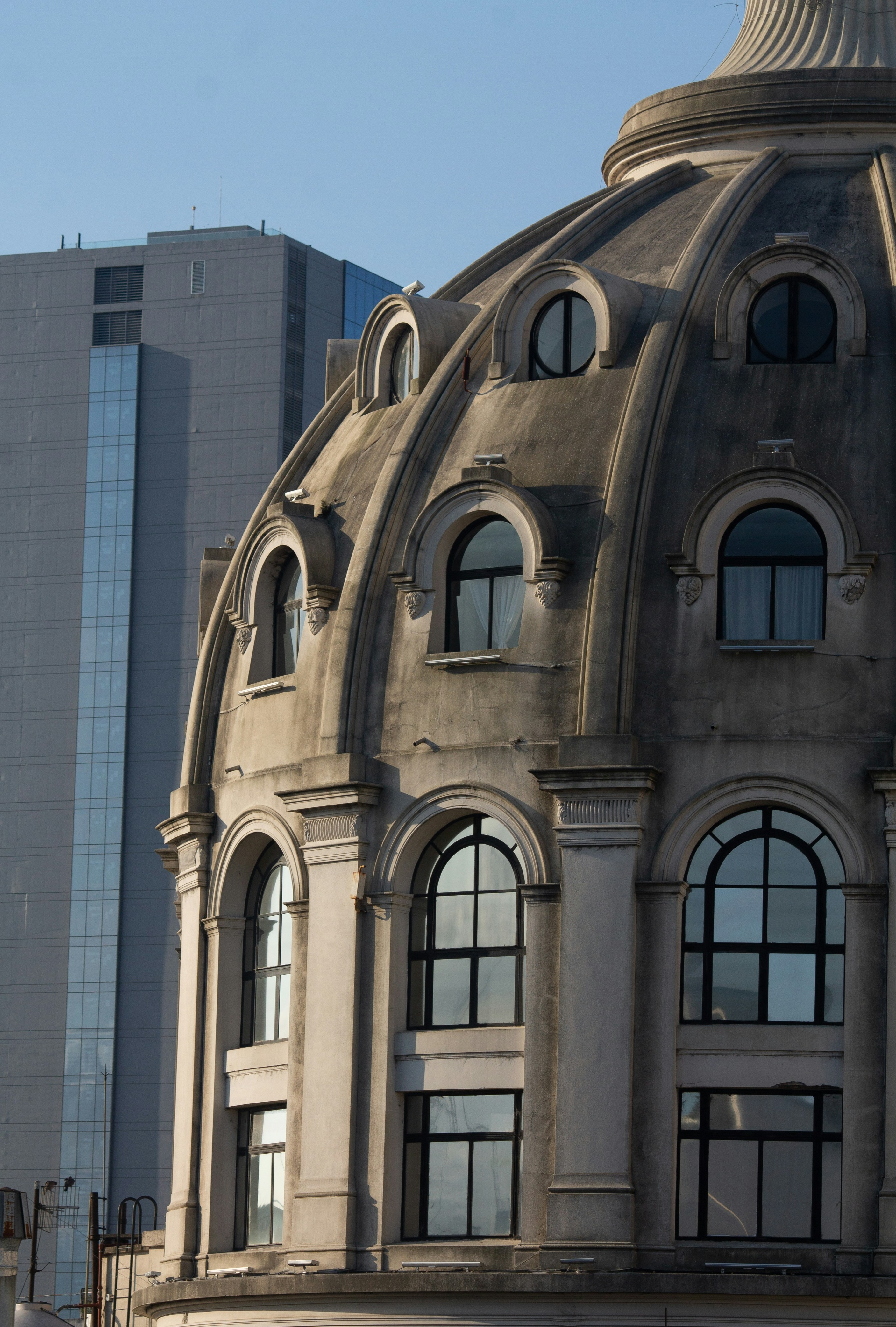 Historic dome with ornate windows juxtaposed against a modern skyscraper, showcasing a blend of old and new architectural styles.