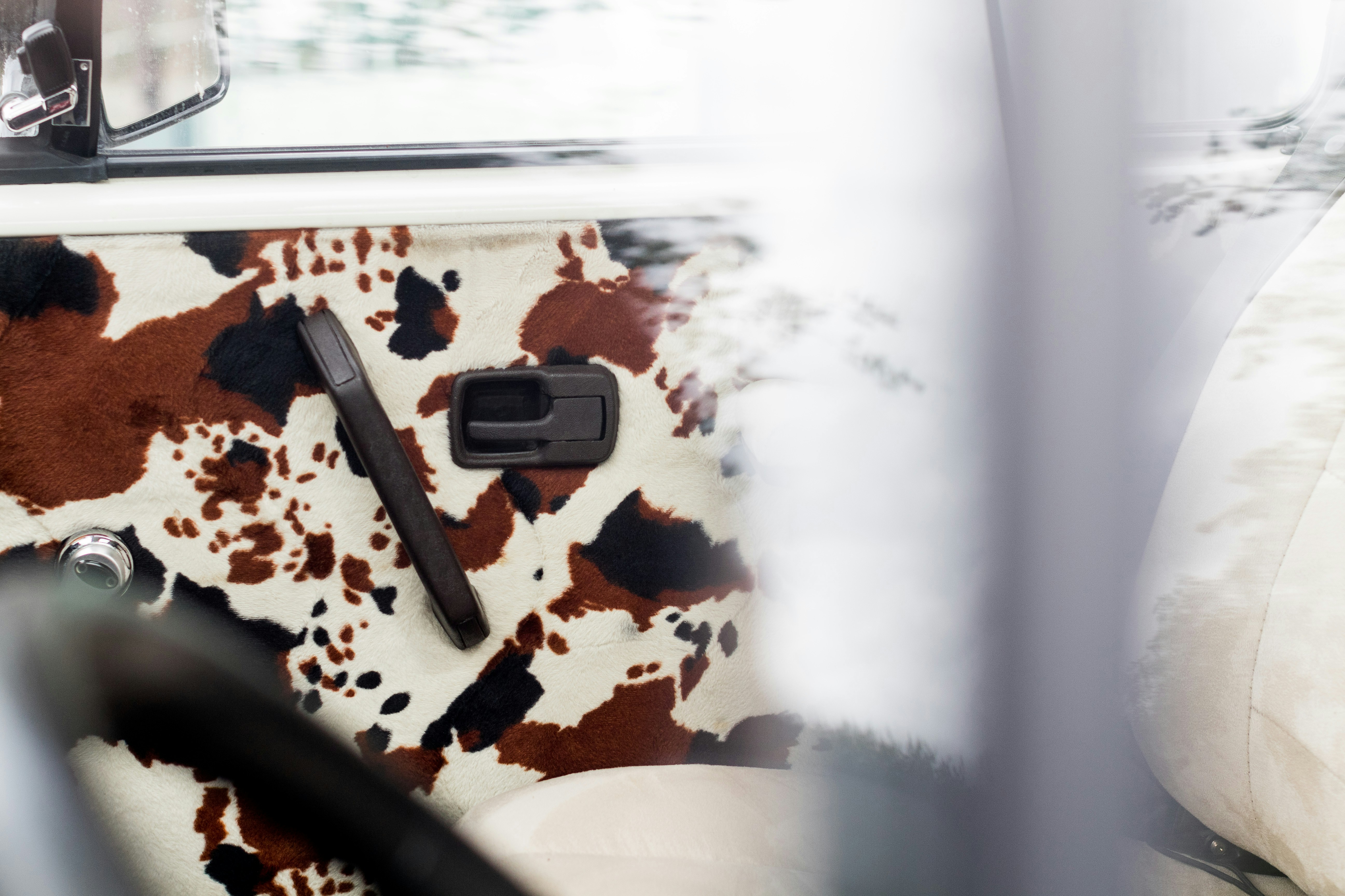 Cowhide-Covered Door Panel and Quiet Latch: A Close-Up of a Vintage Car Interior