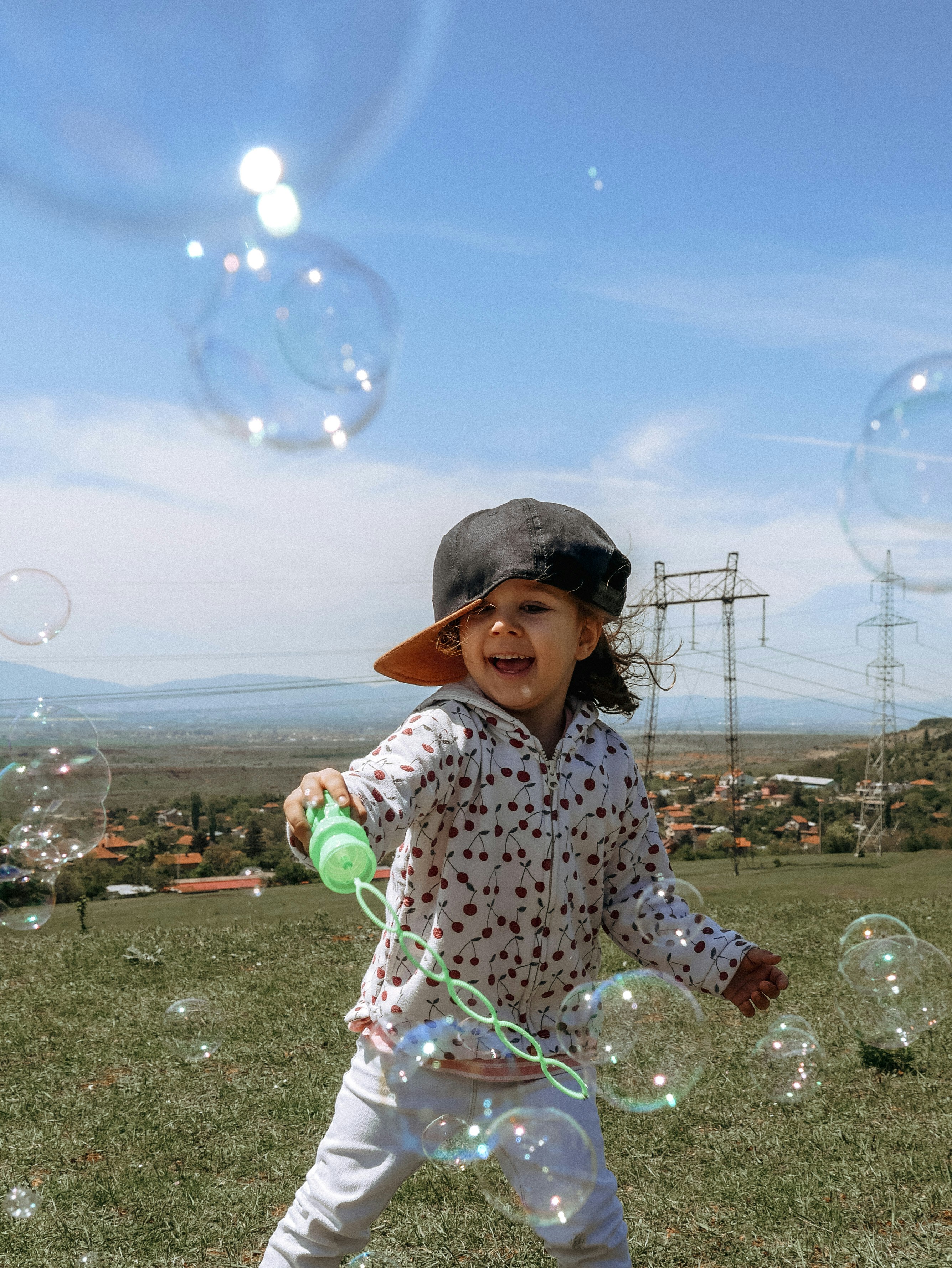 Bubble Chasing Under a Sunny Horizon: A Child's Playful Dance with Floating Orbs