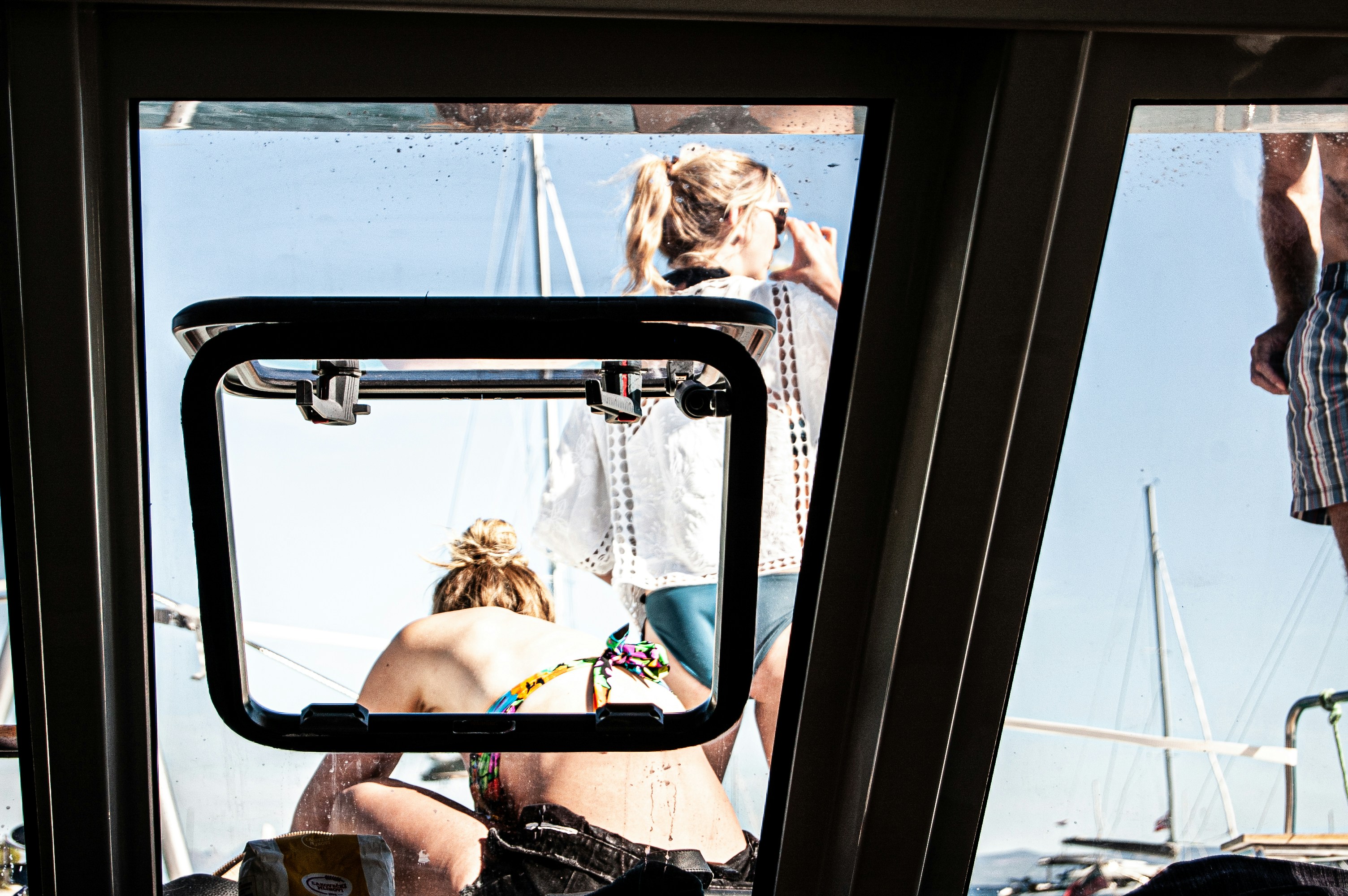 Framed in Glass: A Sunlit Marina Scene Through a Boat Cabin Window
