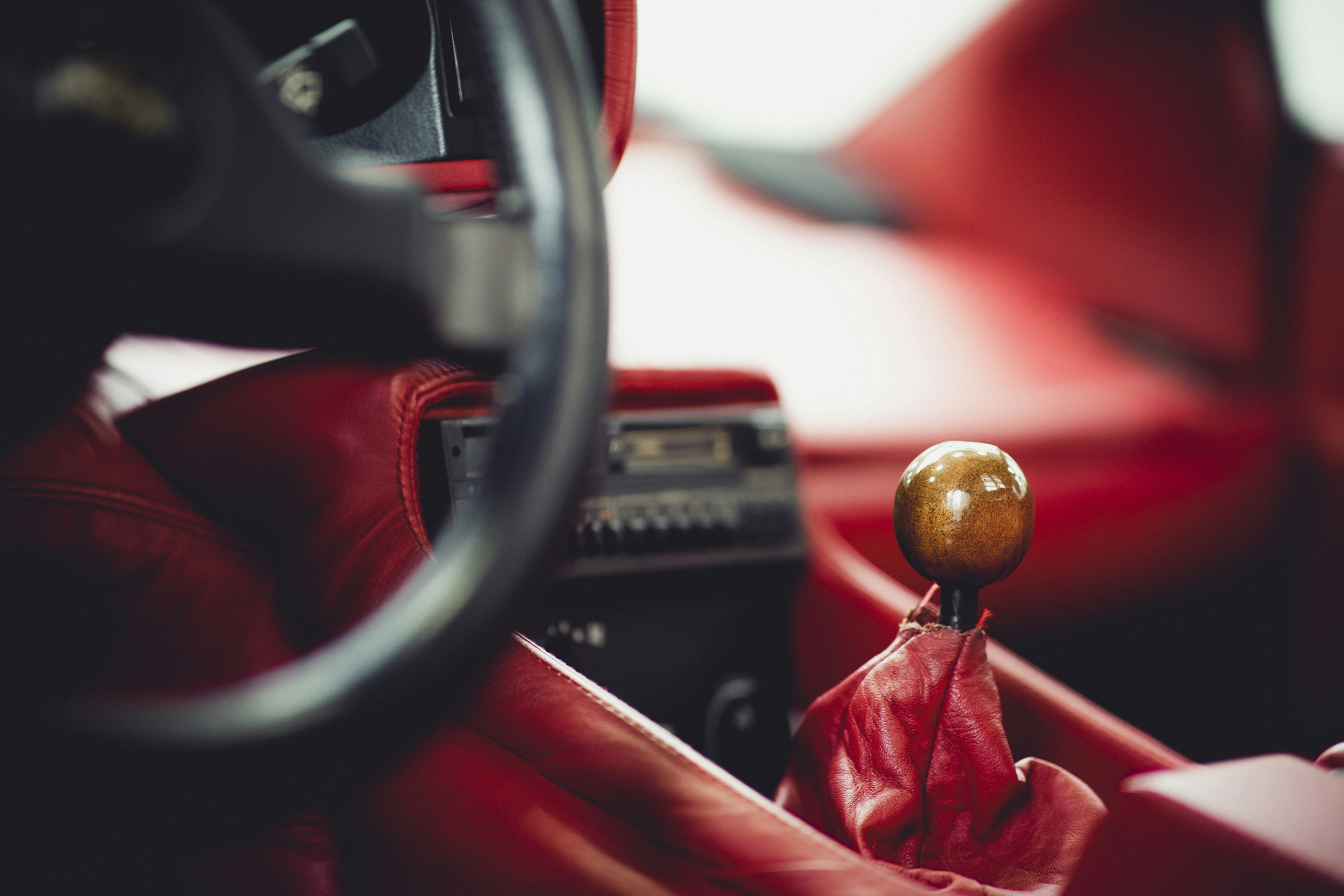 Close-up of a vintage car's interior, showcasing a leather-wrapped gear shift and plush red upholstery.
