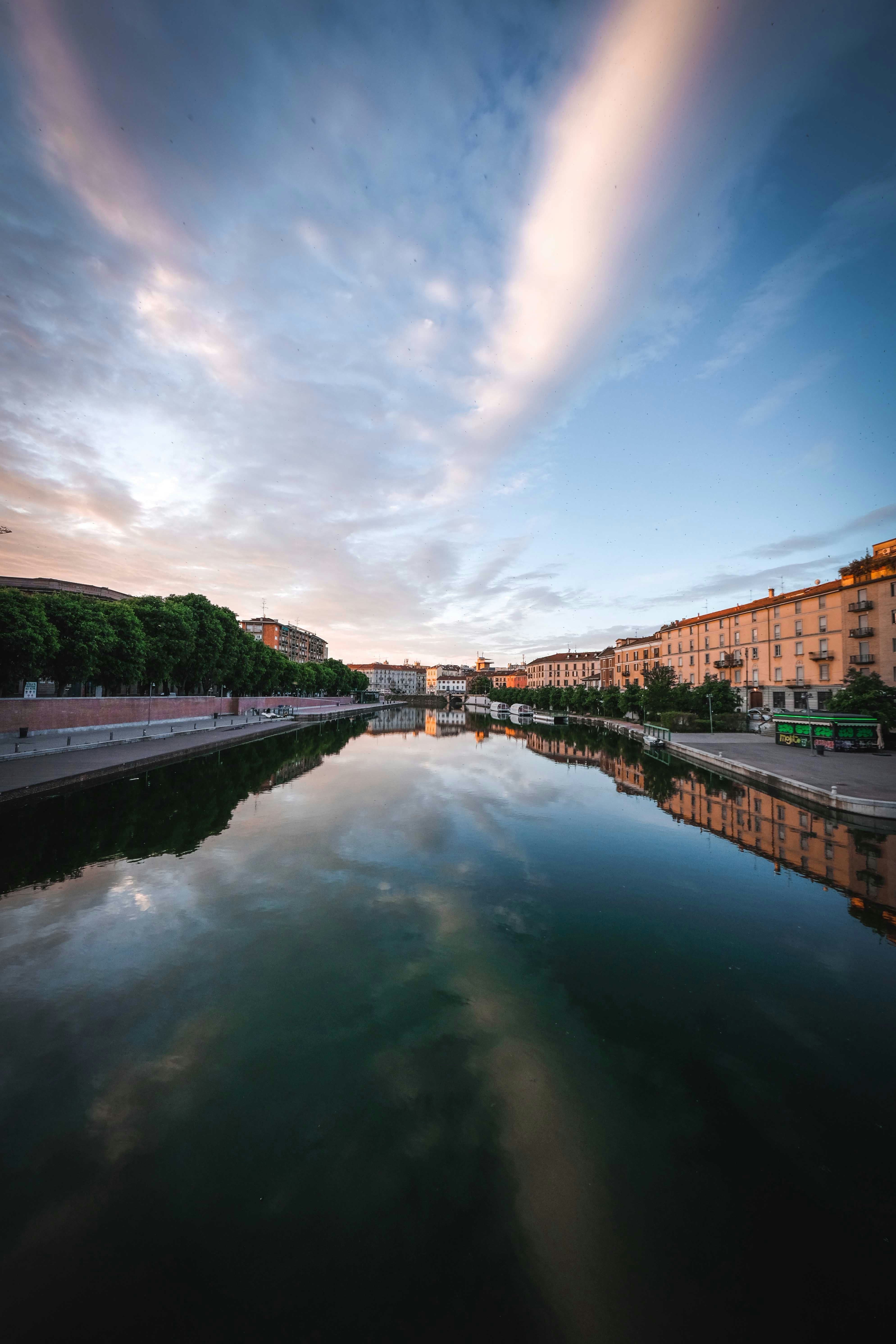 River between green trees and buildings under blue sky during daytime ...