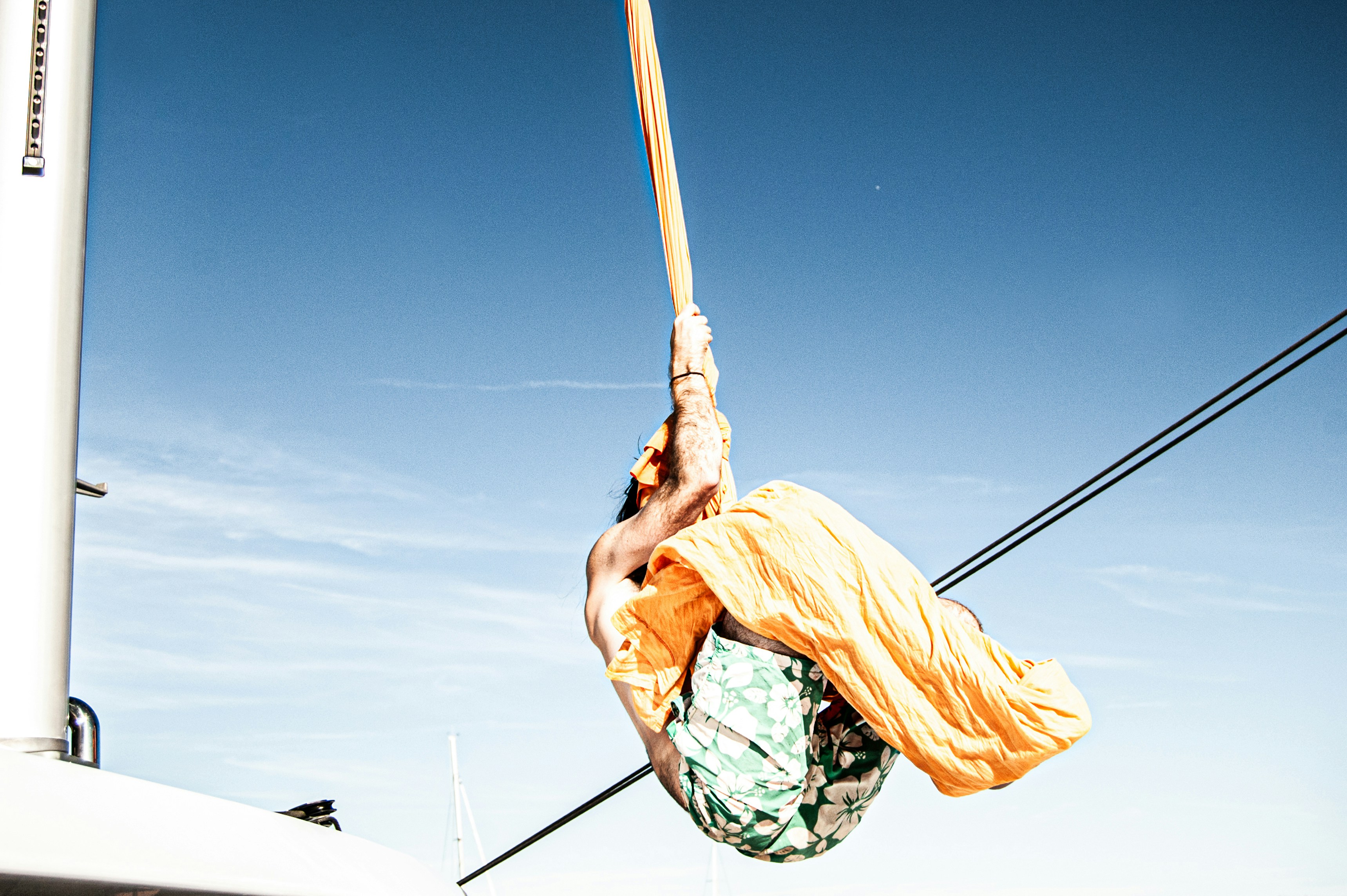 Orange Draped Acrobat Arcs Across a Clear Blue Sky