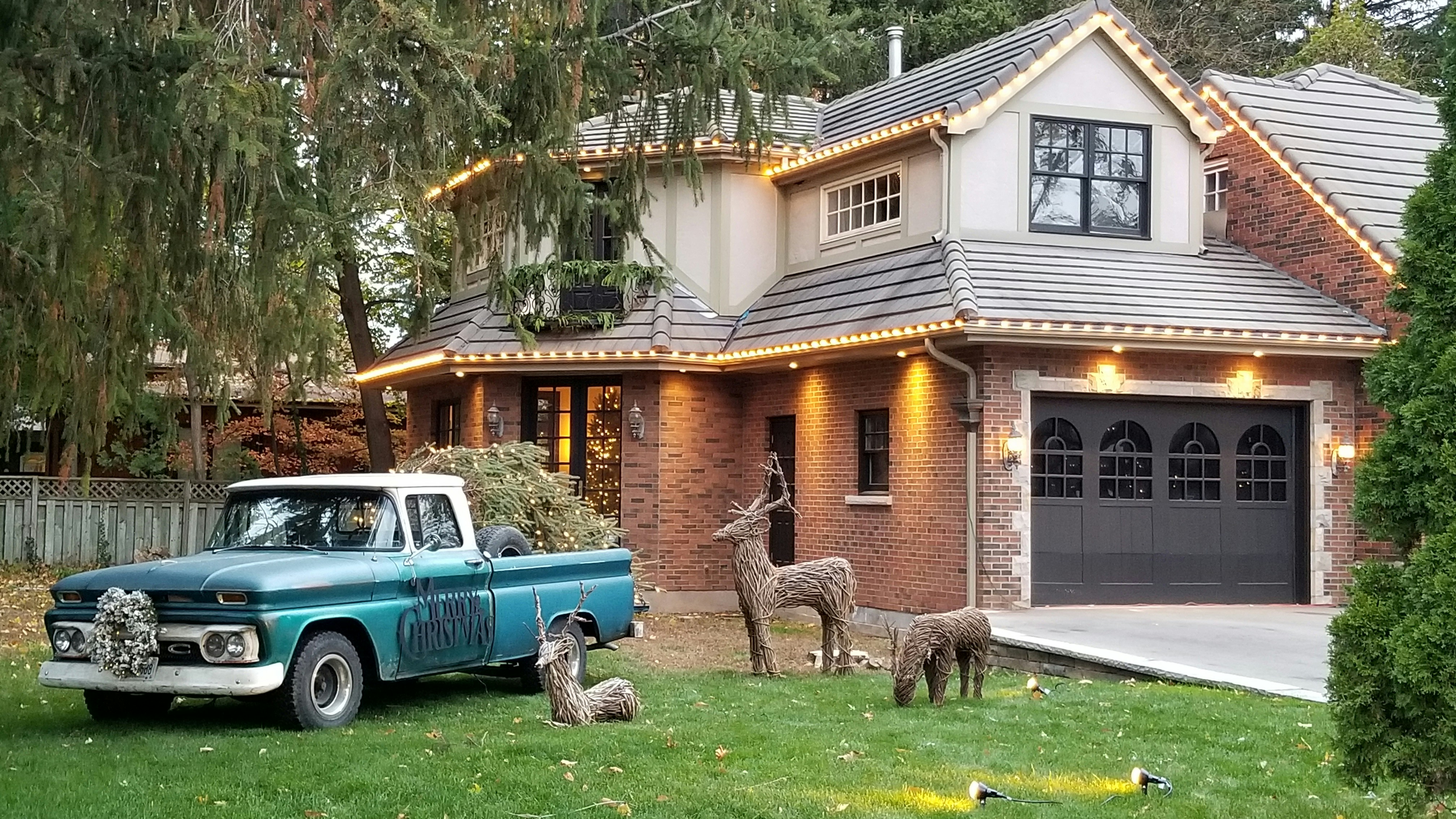 Lived-in Charm: A teal vintage truck beside a two-story brick home with decorative deer