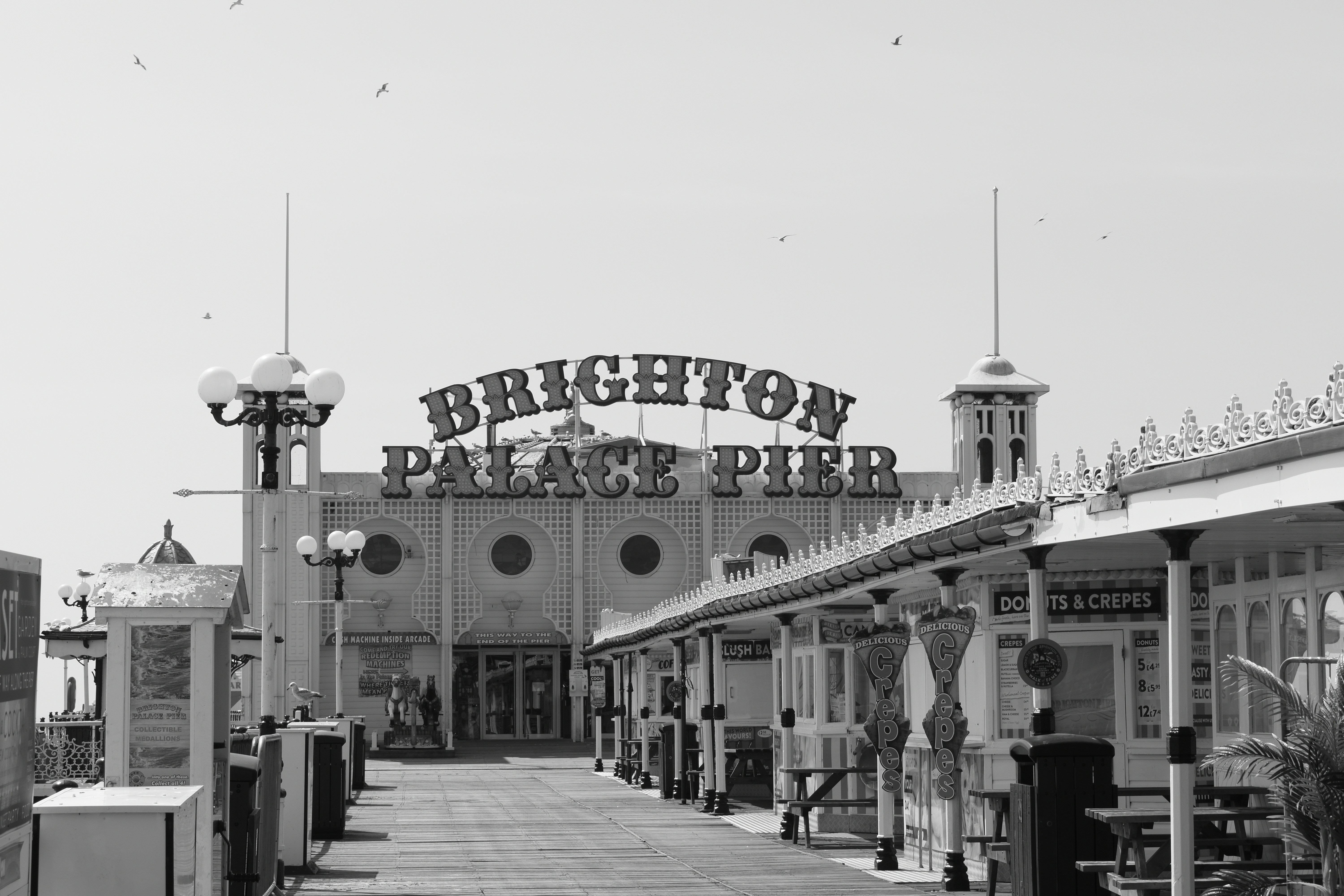 Brighton Palace Pier entrance showcasing its iconic signage, flanked by vintage-style architecture along the boardwalk.