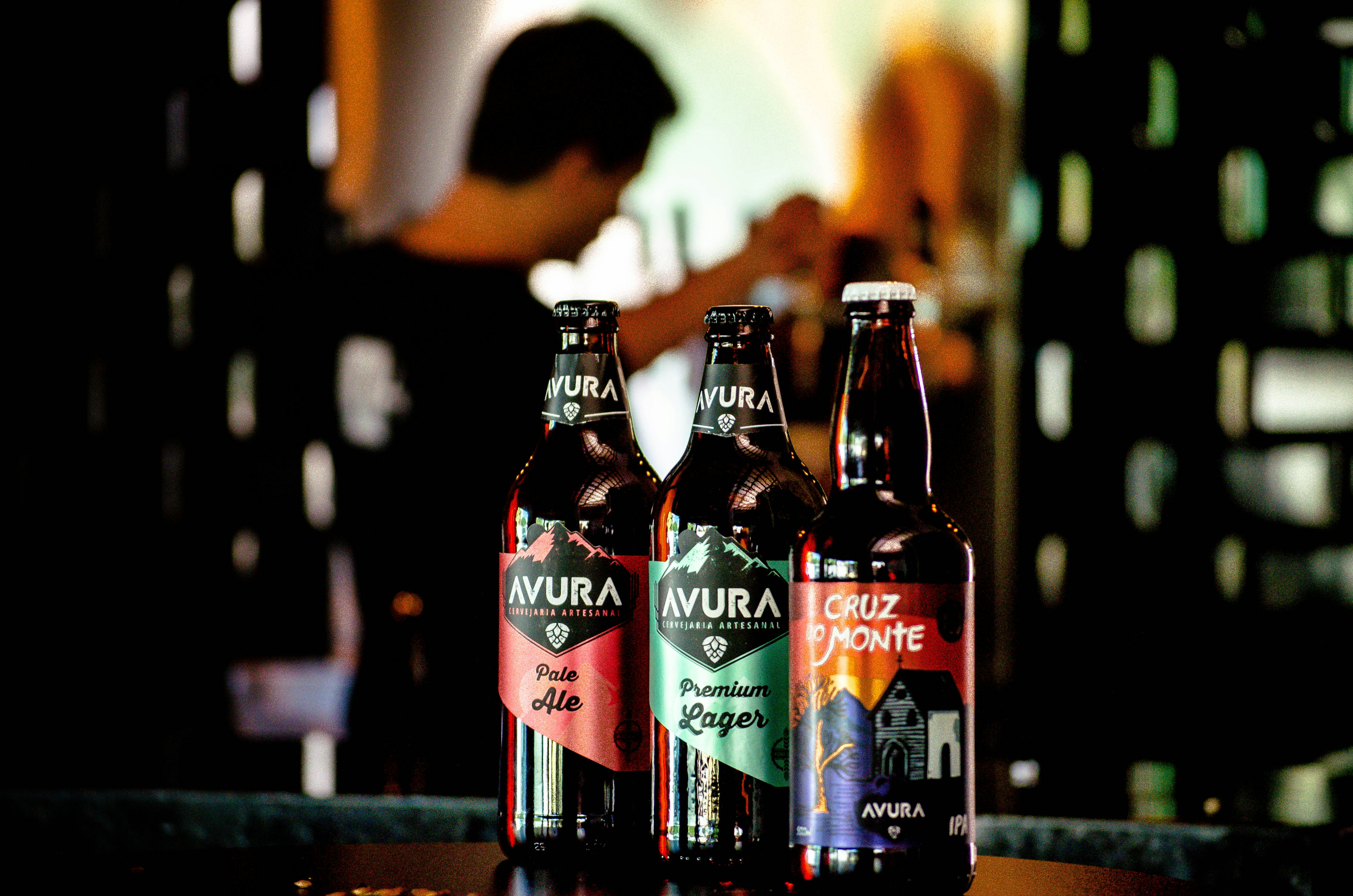 Three Avura Bottles on a Bar Against a Blurred Crowd