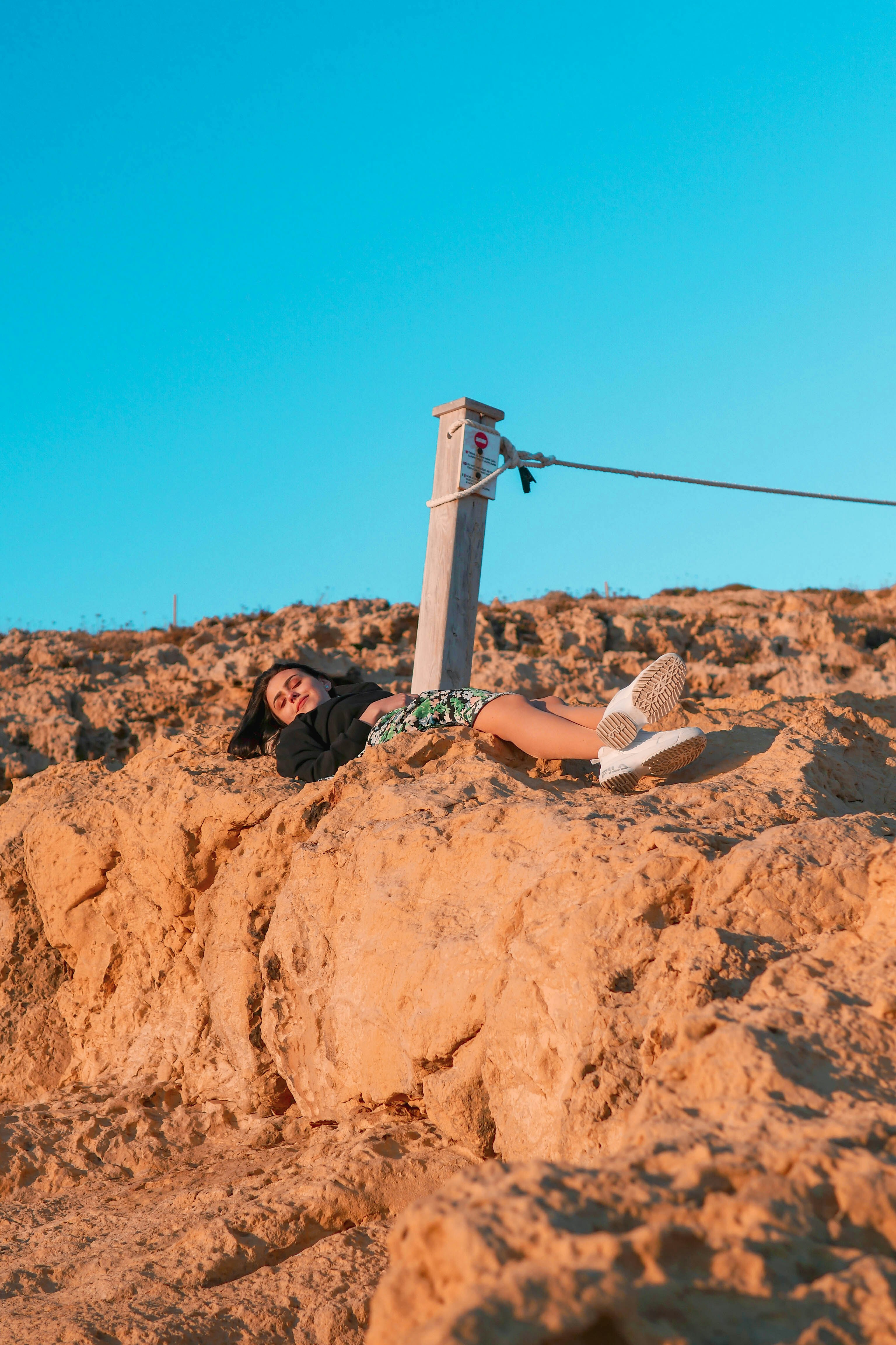 Dune Rest: A Figure Reclines Beside a Weathered Post Under a Clear Blue Sky