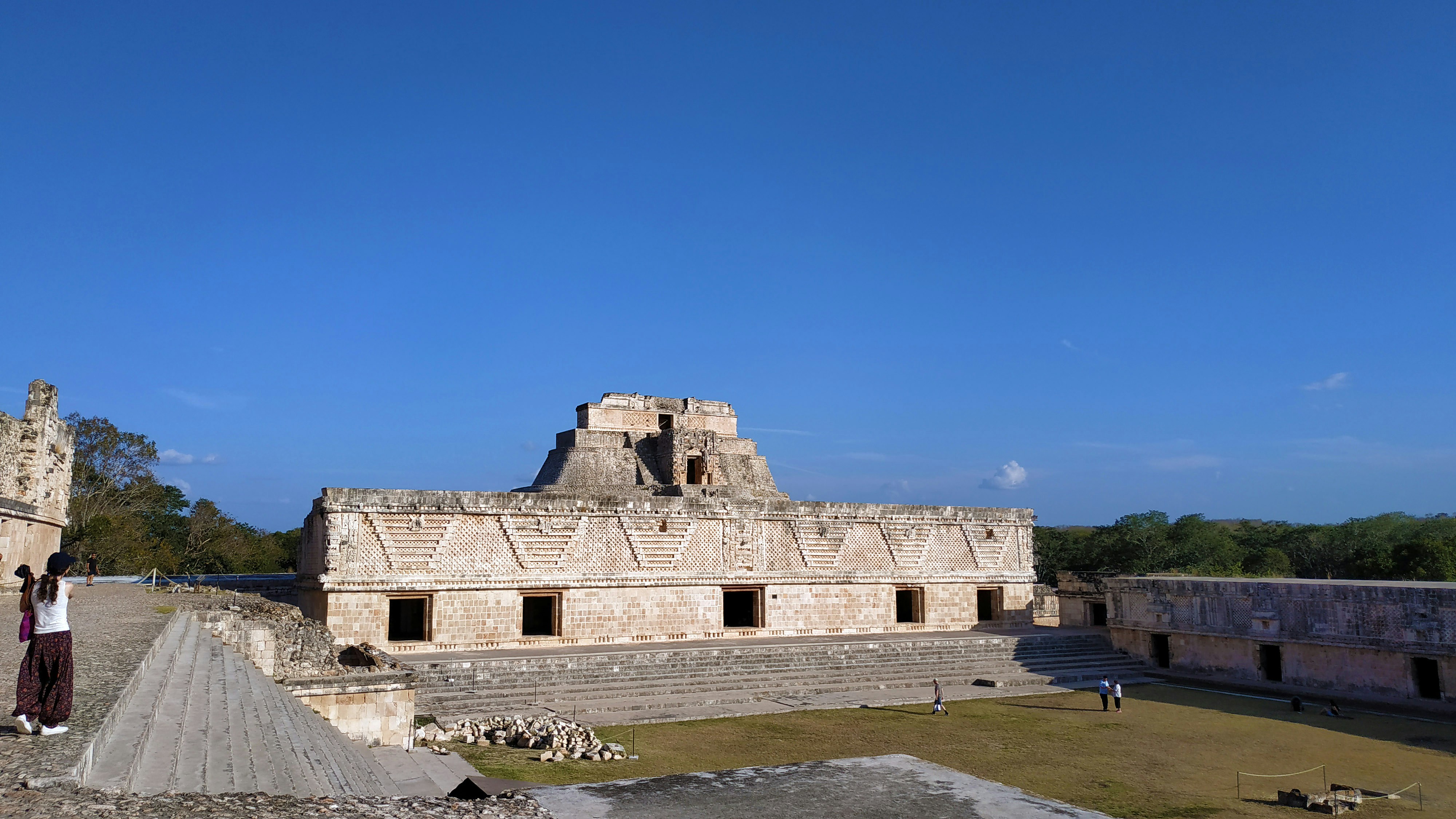 Ancient stone structure under a clear blue sky, surrounded by grassy terrain.