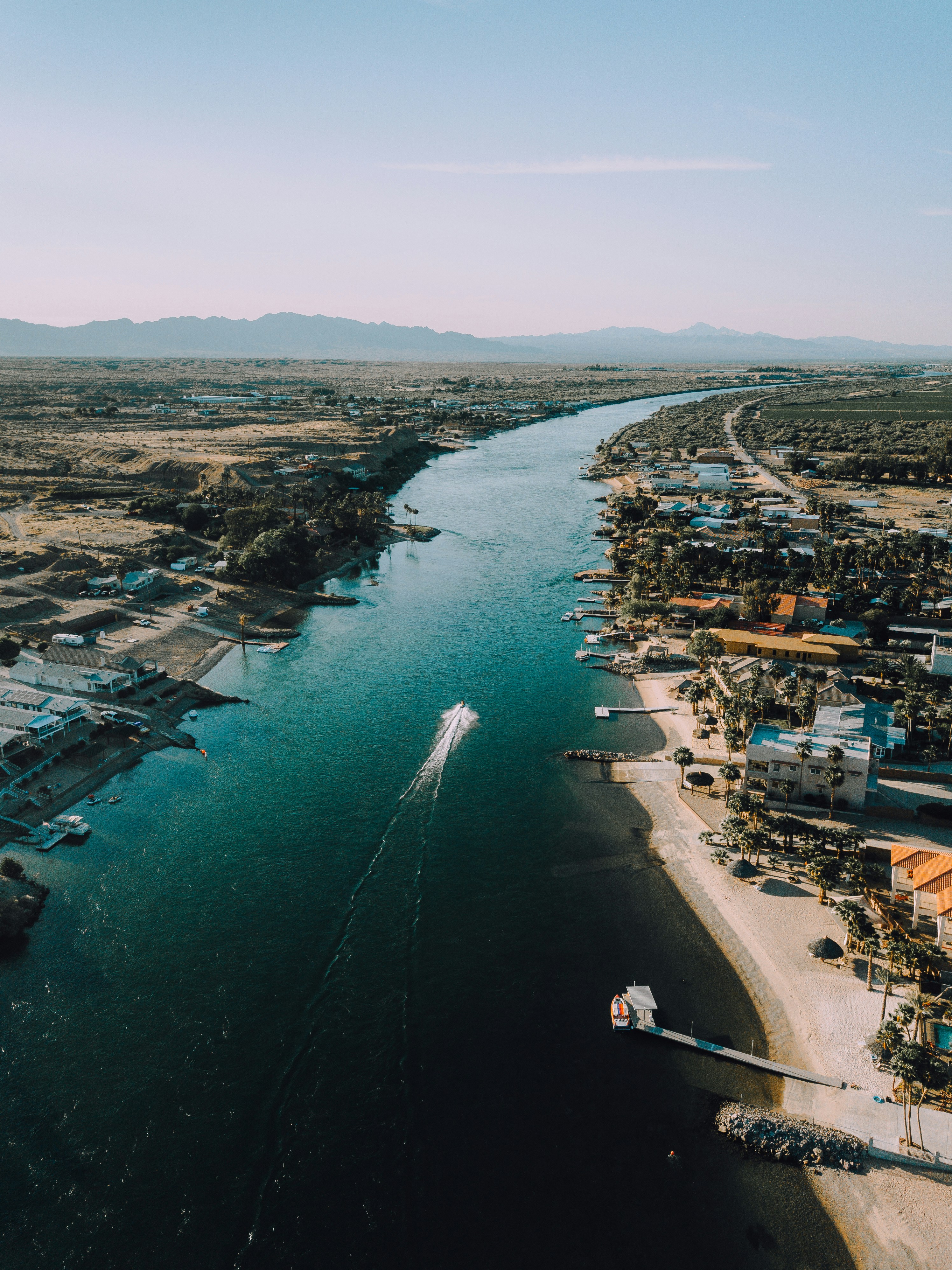 Aerial view of a winding waterway bordered by vibrant homes and lush greenery, showcasing the tranquil beauty of the landscape.