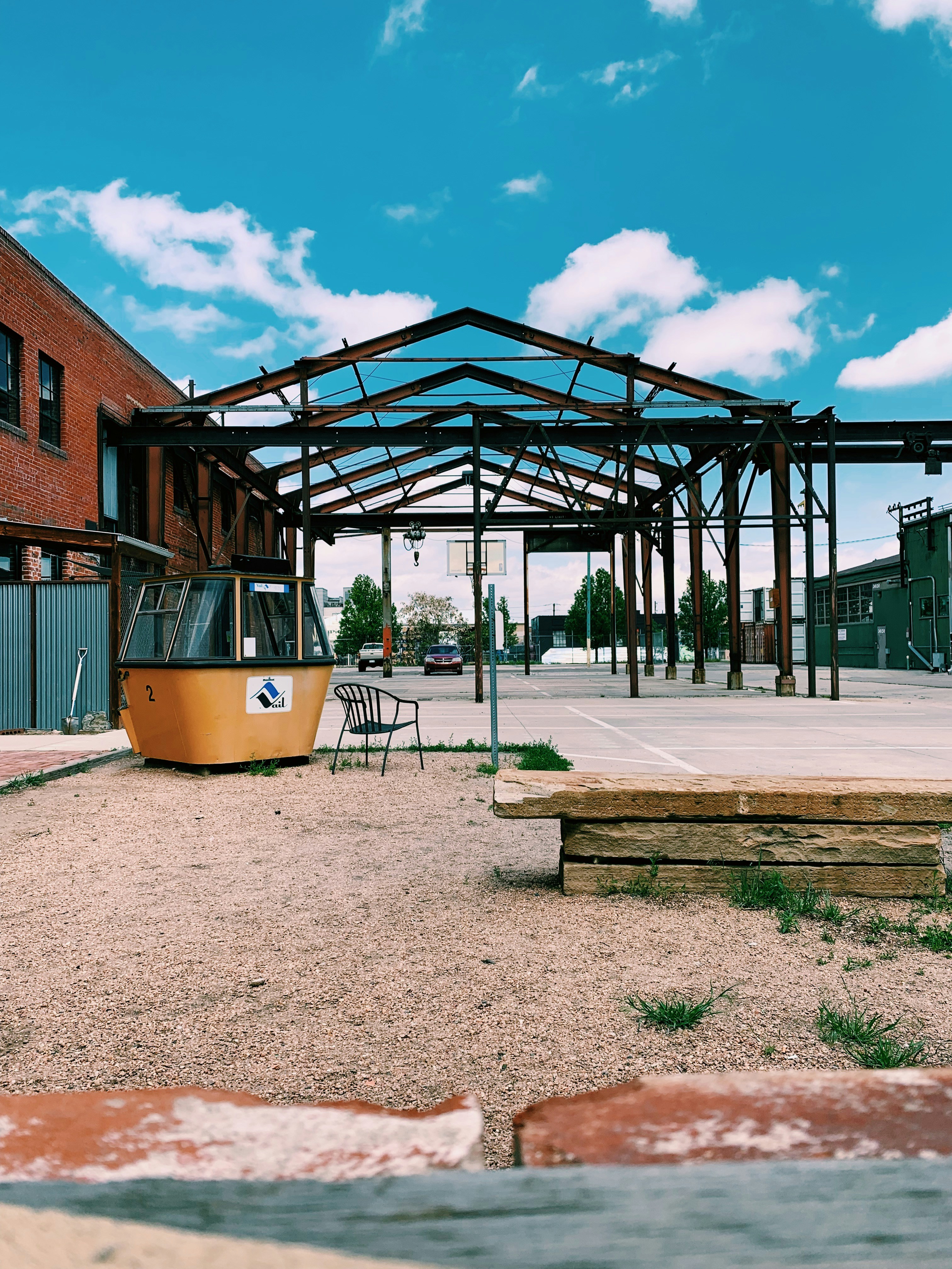 Lattice of Steel and Rust: An Industrial Yard Framed by a Lone Orange Cart