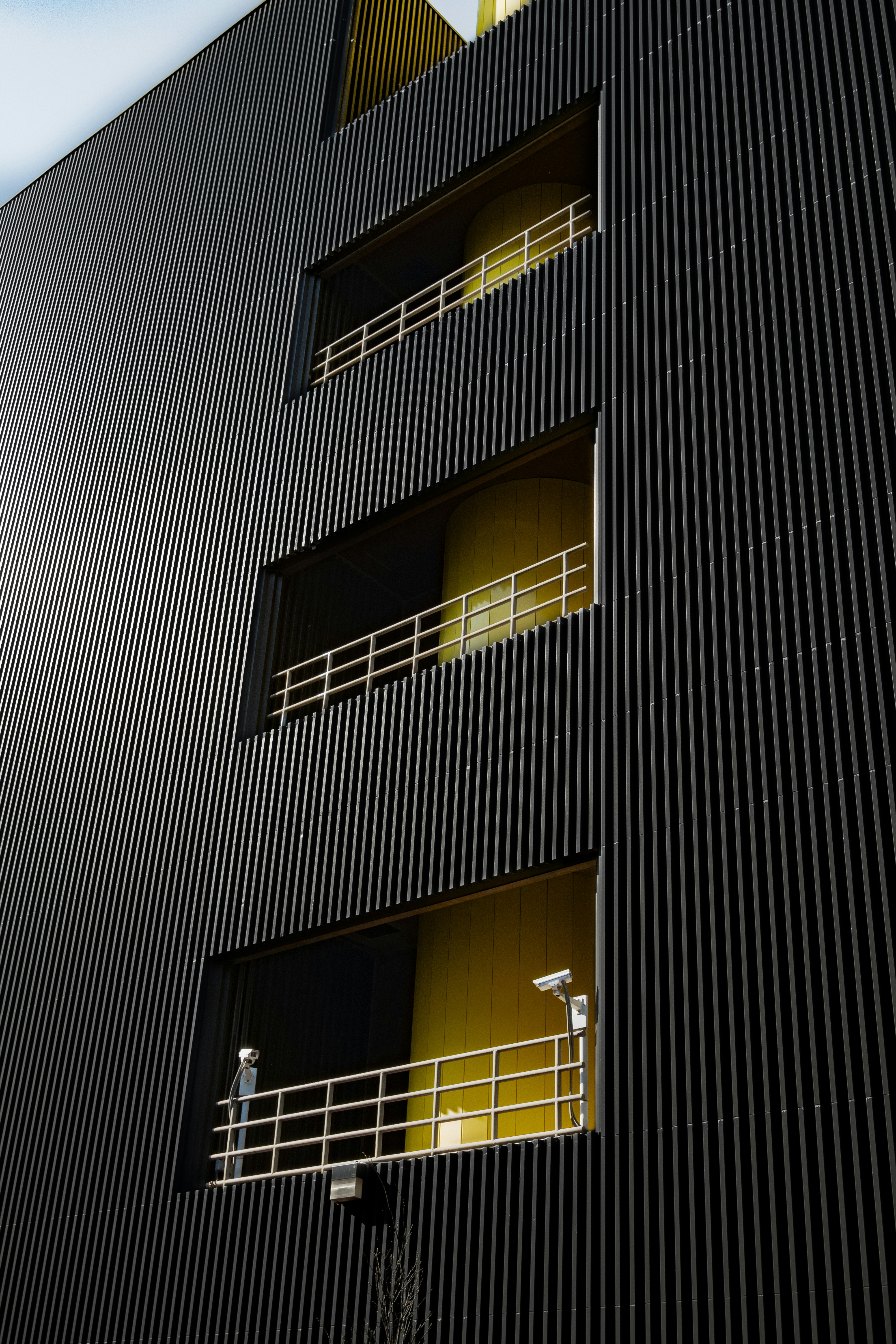 Yellow Atrium Behind a Vertically Ribbed Facade