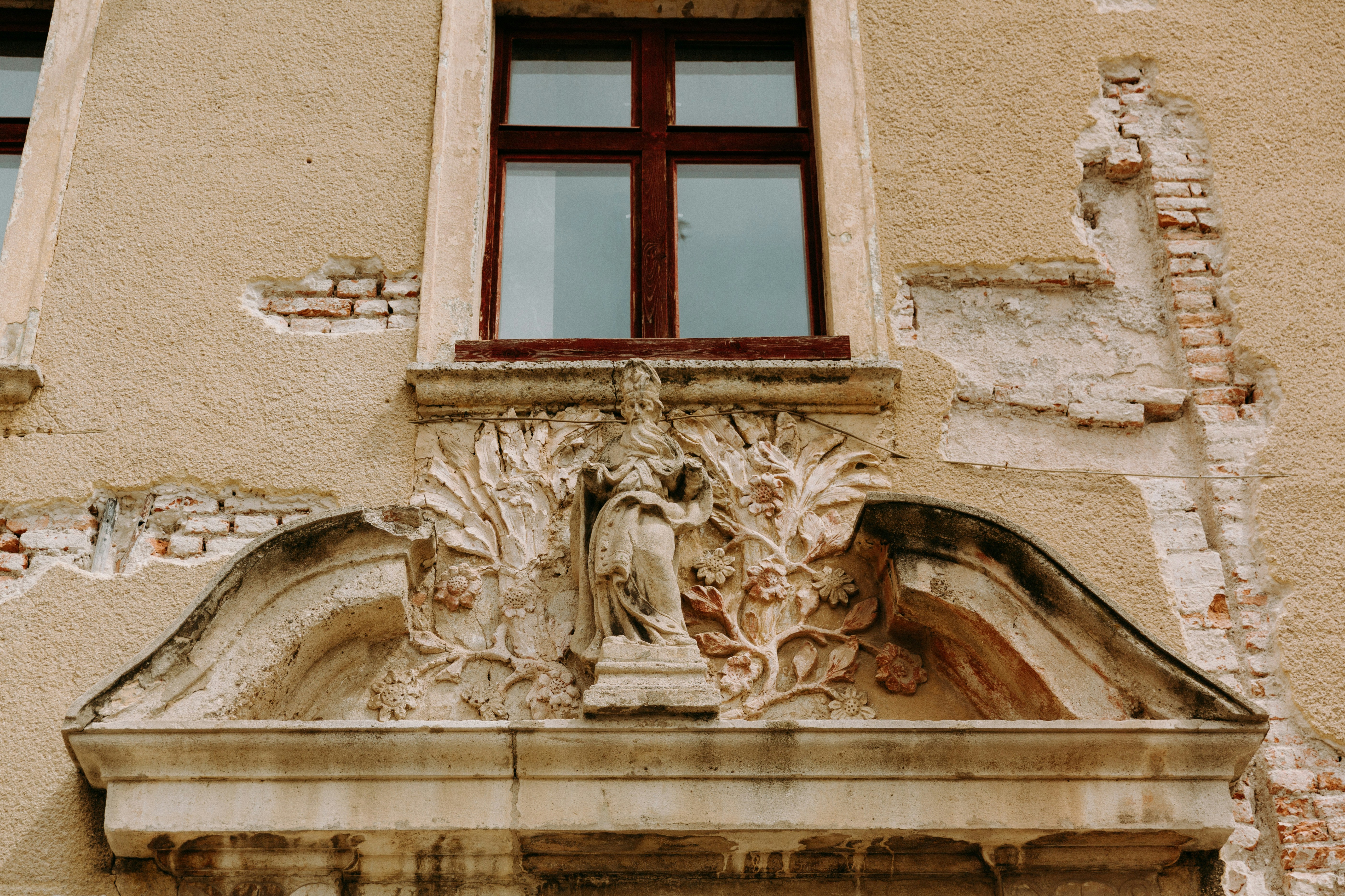 Weathered Frieze: Central Statue Emerges from a Crumbling Facade