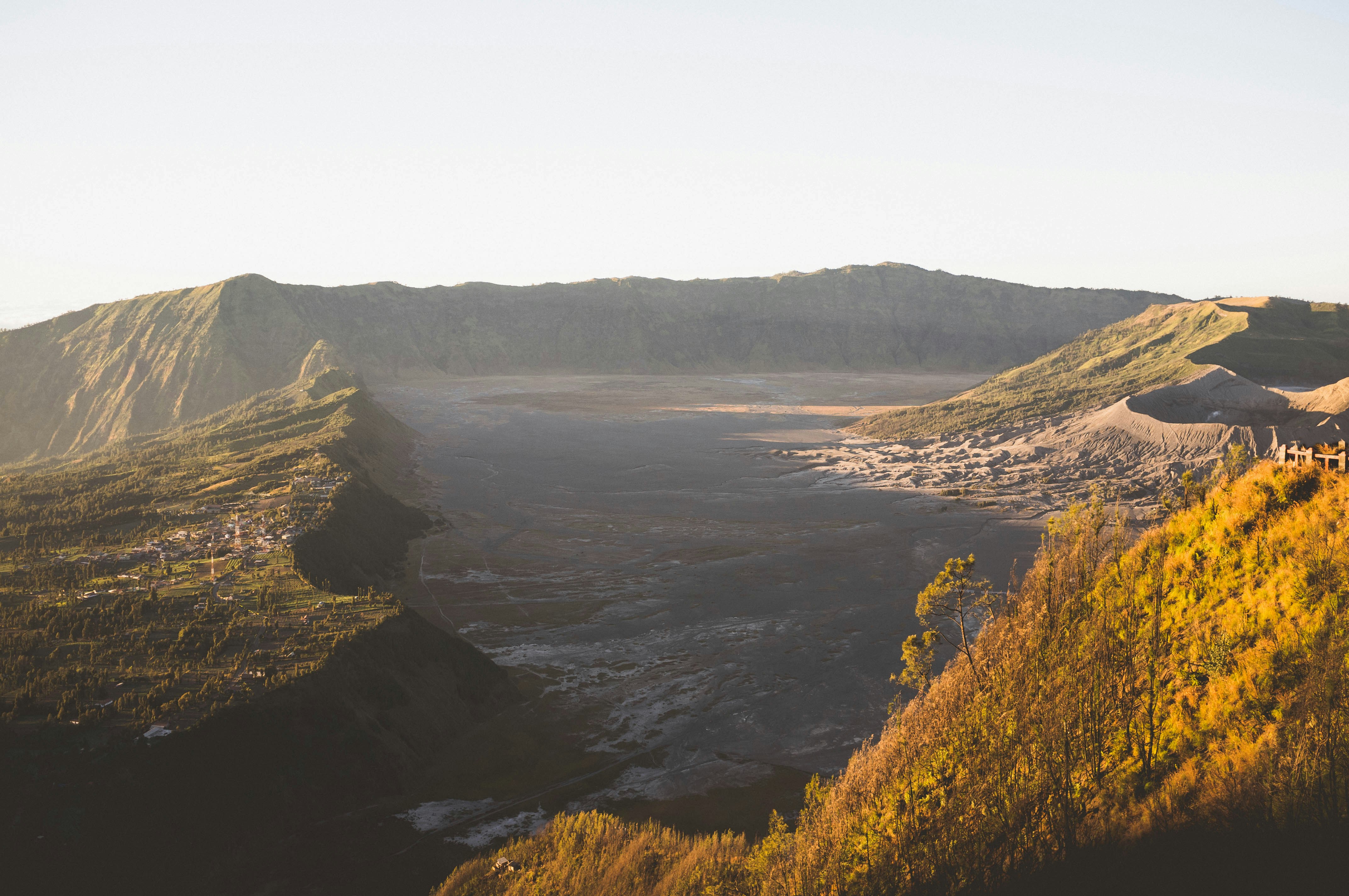 Expansive view of Mount Bromo's crater and surrounding landscape bathed in warm, early morning light.