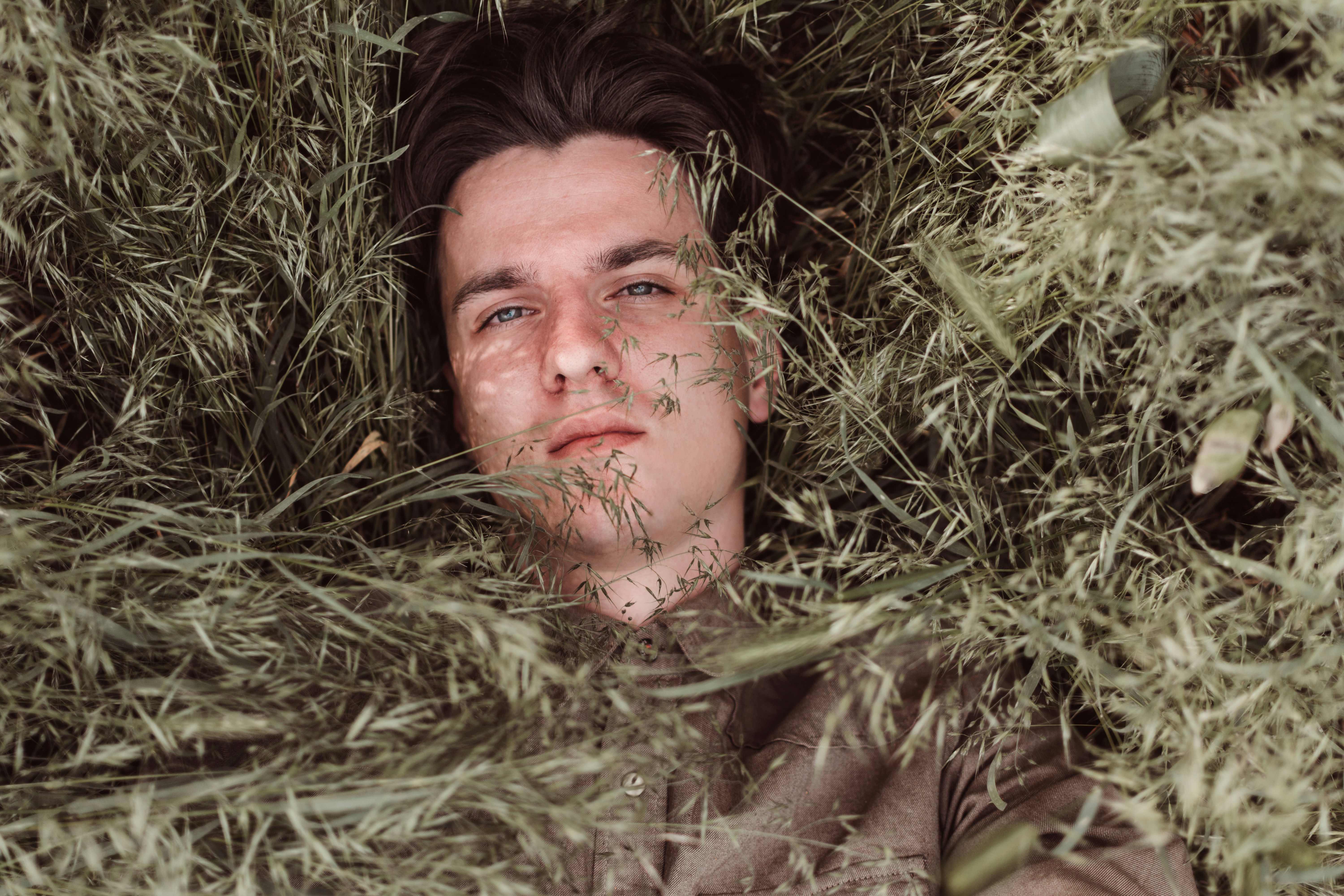man lying on green grass during daytime