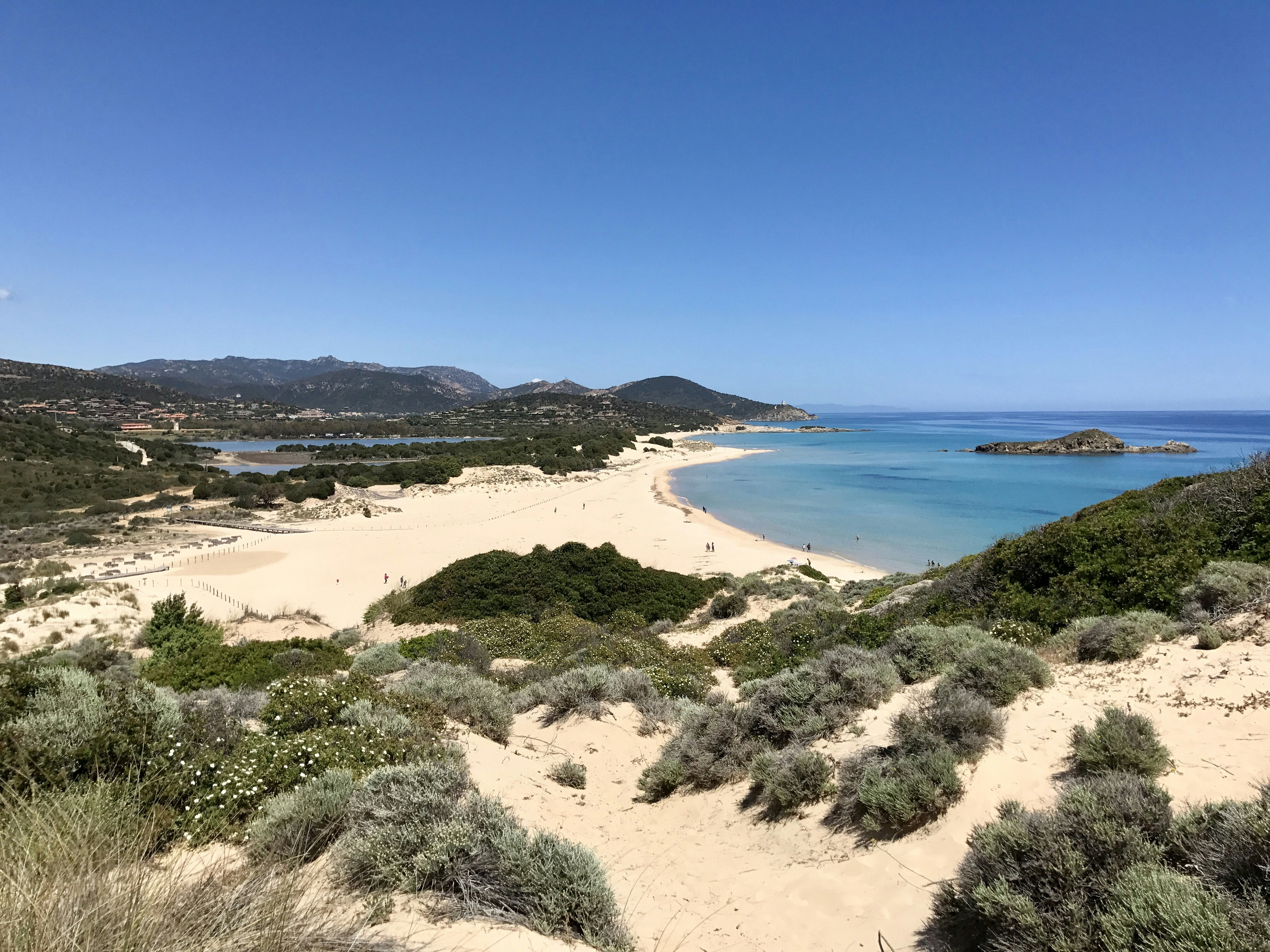 Expansive sandy beach stretching alongside turquoise waters under a clear blue sky.