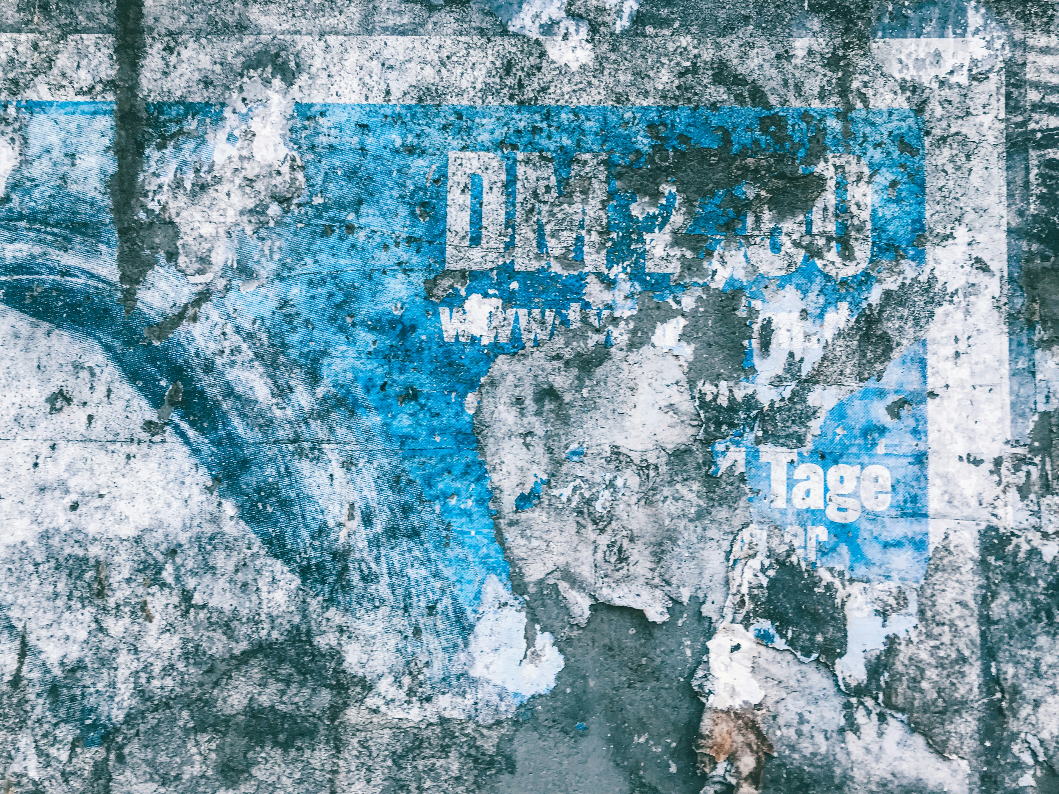 Weathered Blue Poster Remnant on Cracked Wall