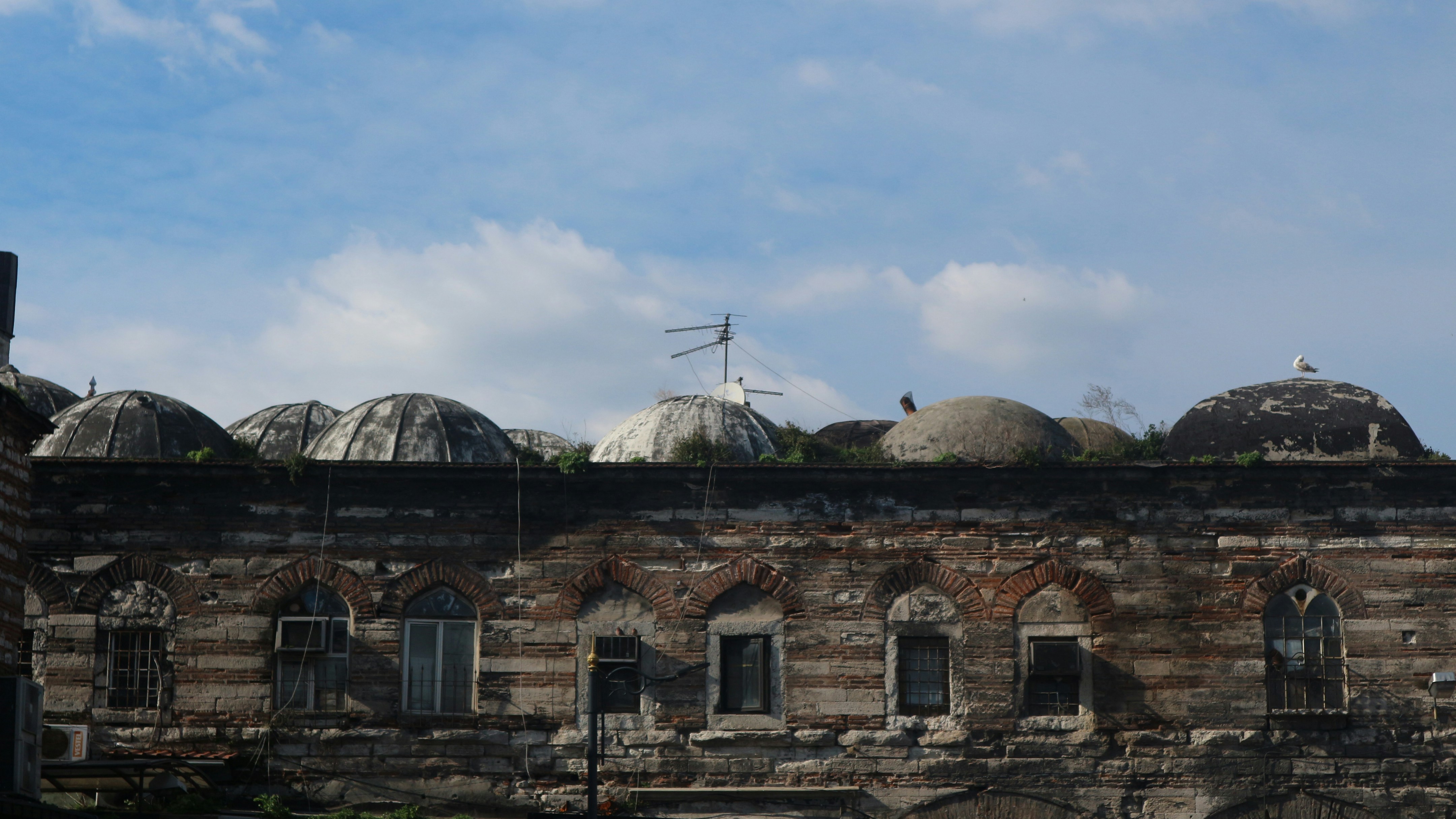 Historic building with weathered domes and windows, showcasing architectural details against a cloudy sky.