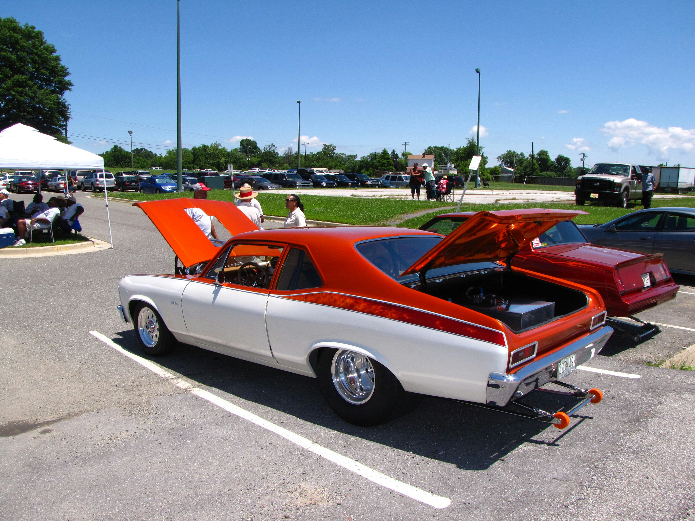 Two-tone classic car on display with raised hood at outdoor car show