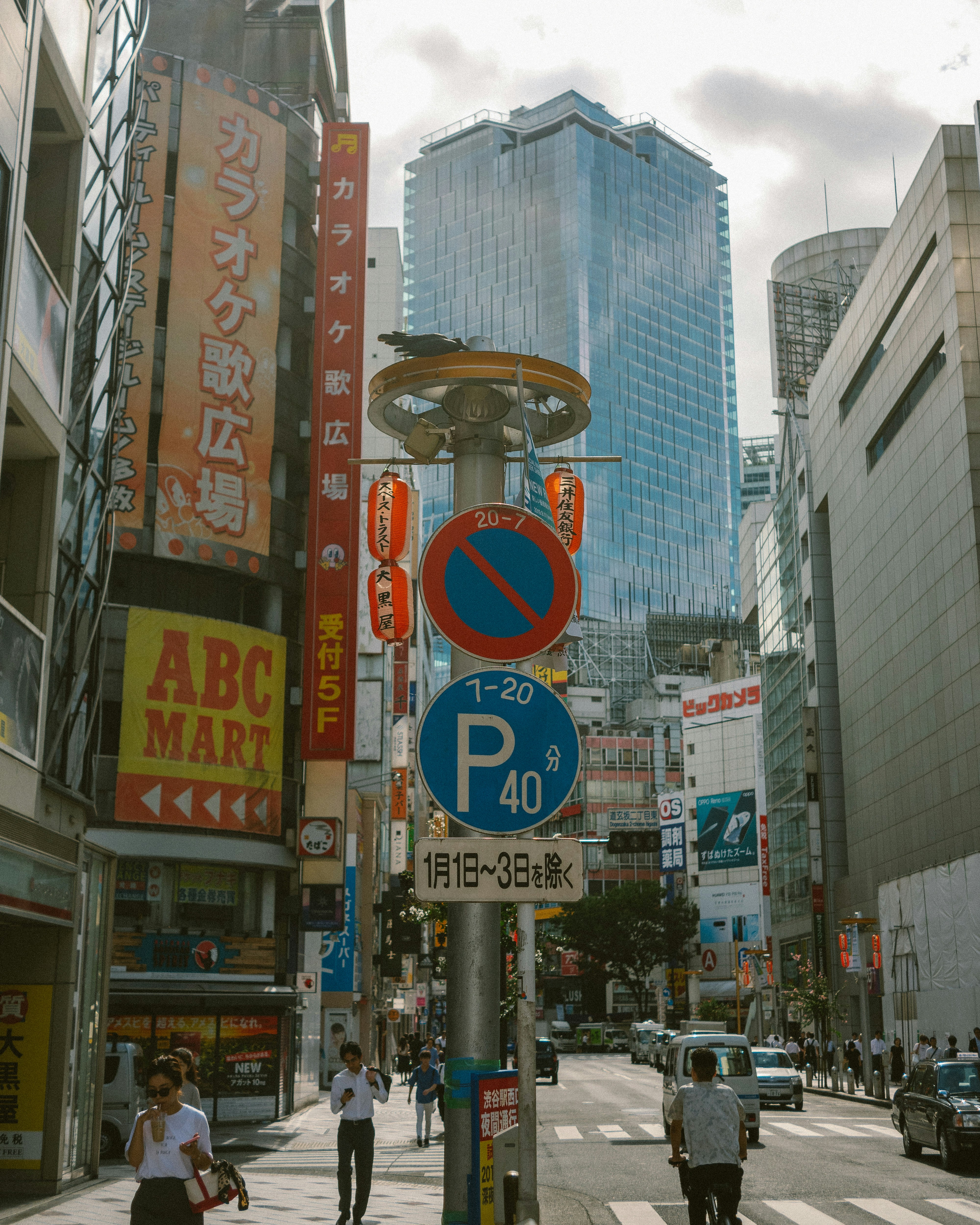 Vibrant city street scene featuring colorful signage and traffic signals amidst modern skyscrapers. The hustle of urban life is palpable.
