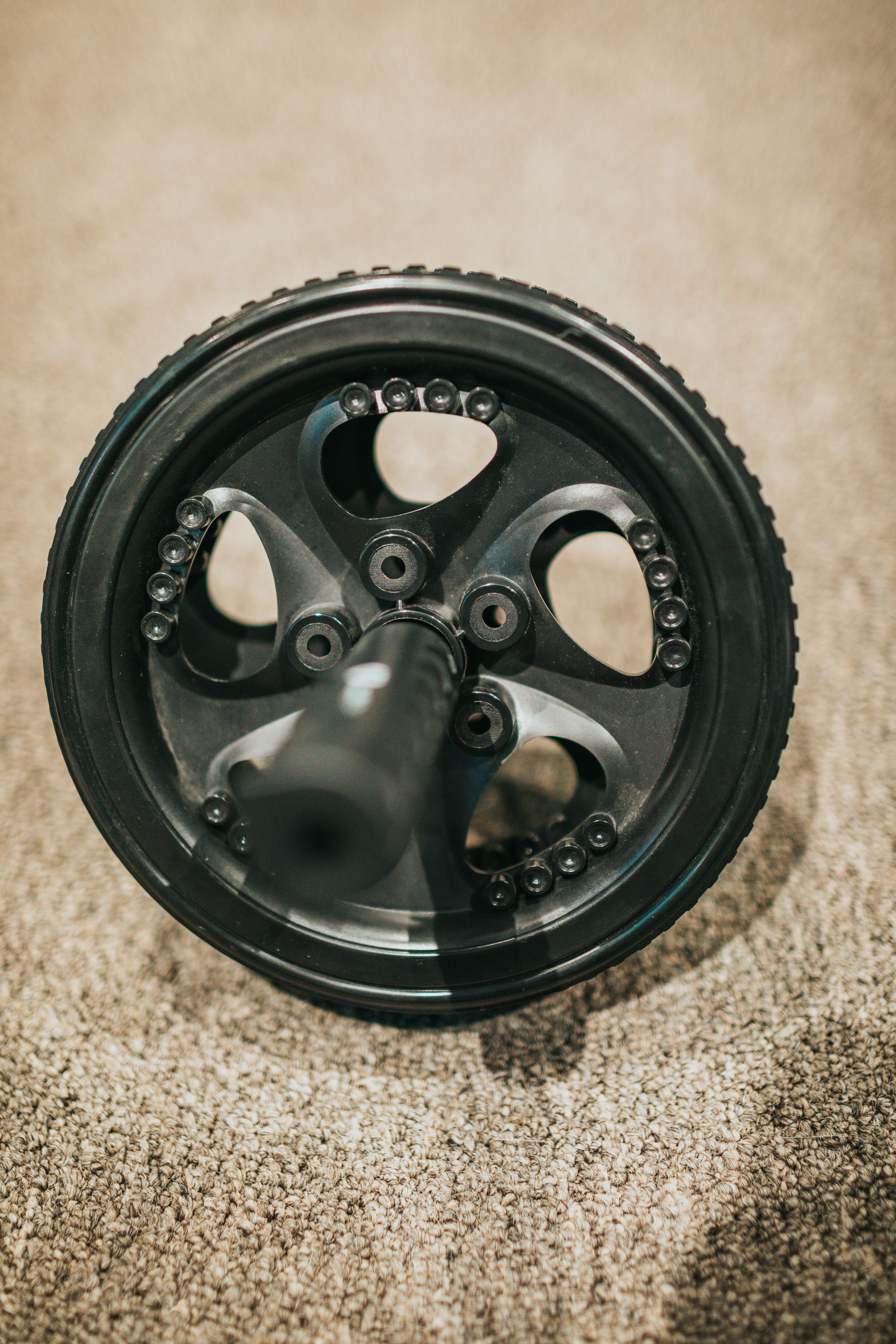 Black exercise wheel with a textured grip, positioned on a soft surface, showcasing its design and functionality.