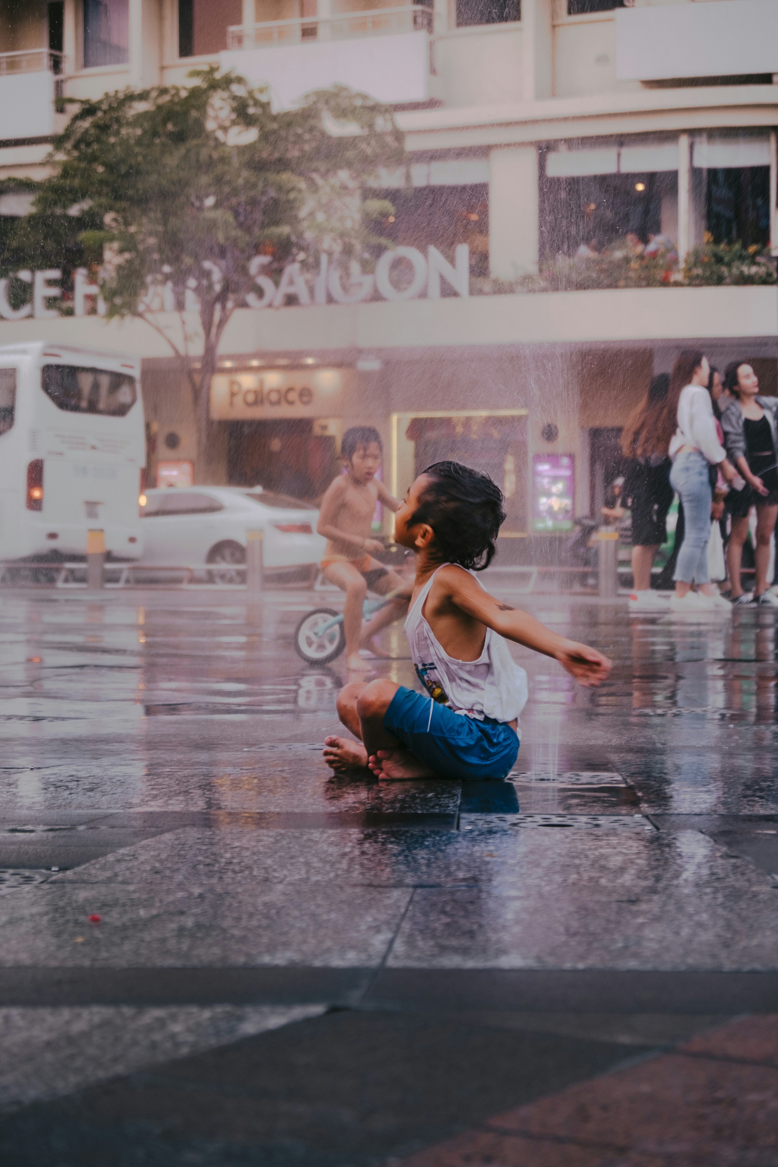woman in blue denim shorts sitting on wet road during daytime