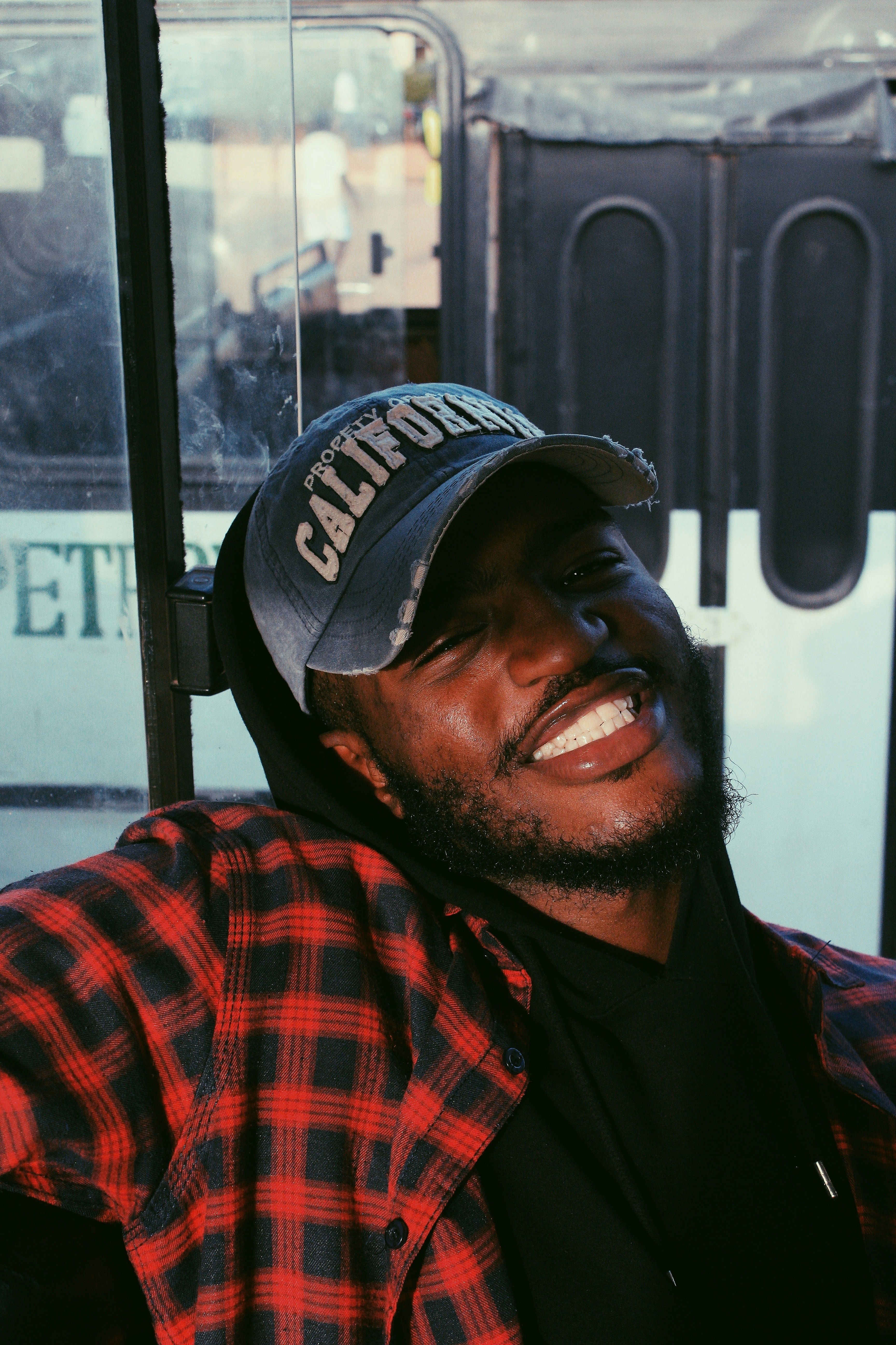 Smiling in the Bus Window: A Candid Portrait in Red Plaid