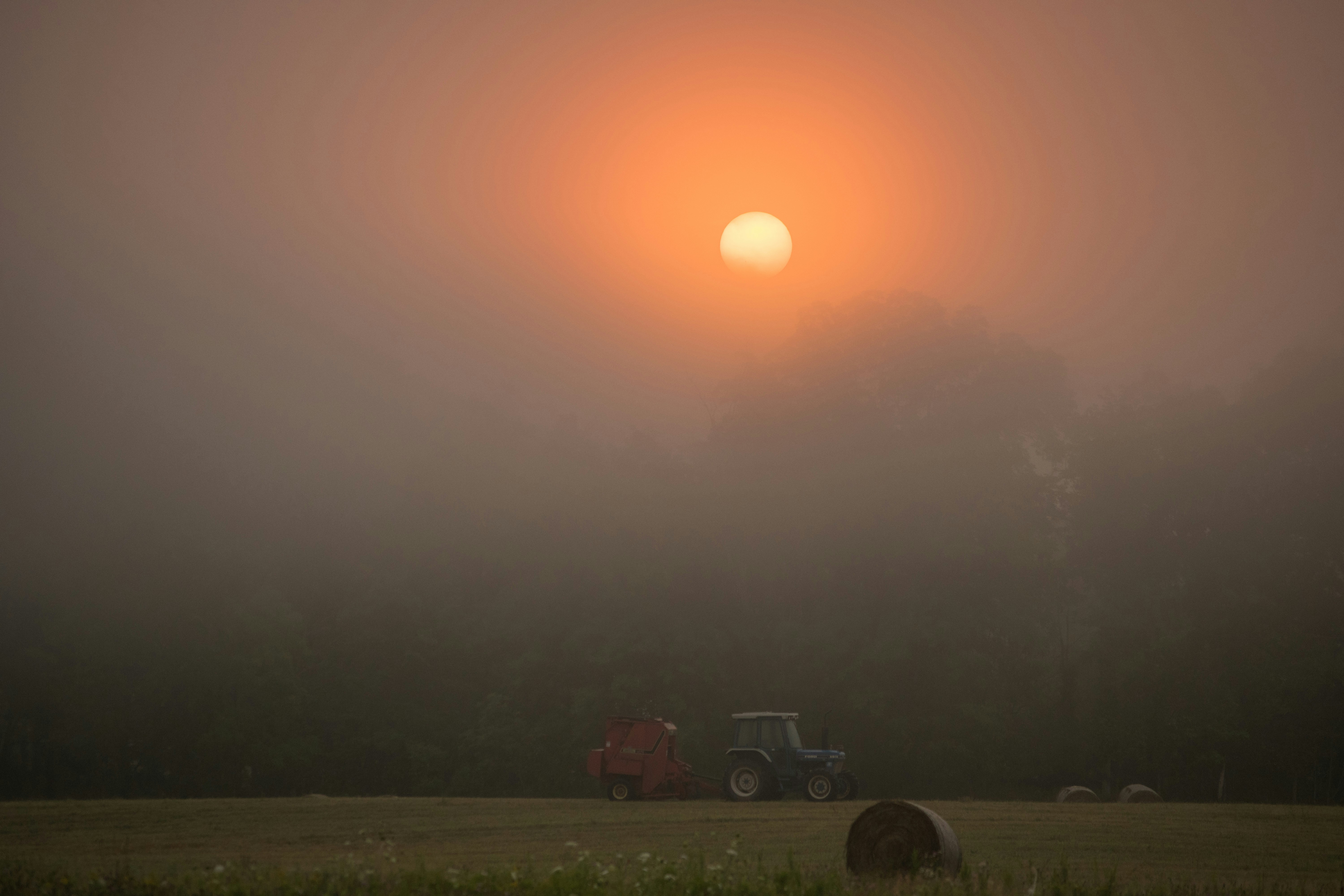 Dawn Veil Over a Fog-Laced Field with Tractors