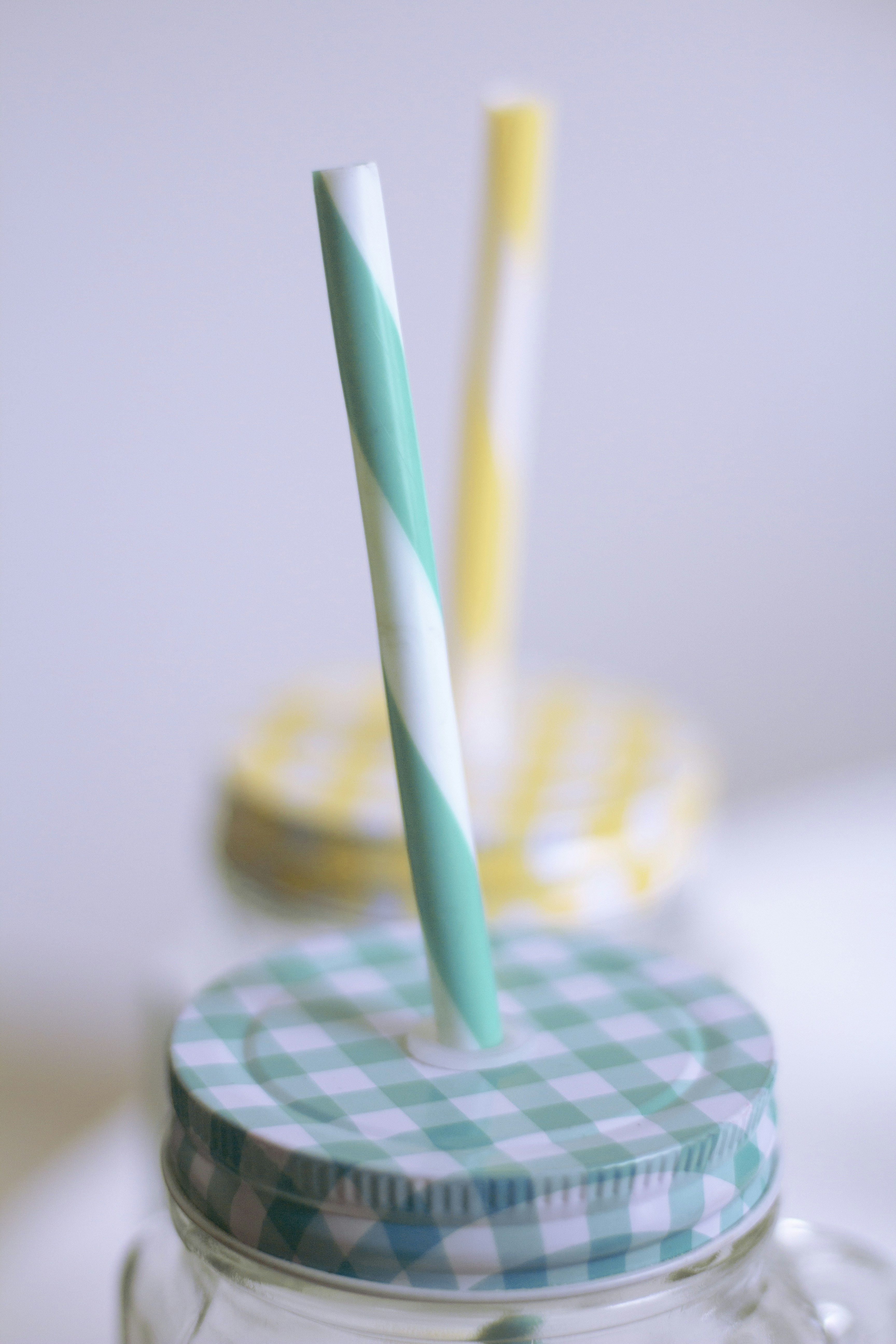 Two jars with patterned lids and colorful straws, creating a cheerful and inviting atmosphere. The focus is on the vibrant straws against a softly blurred background.