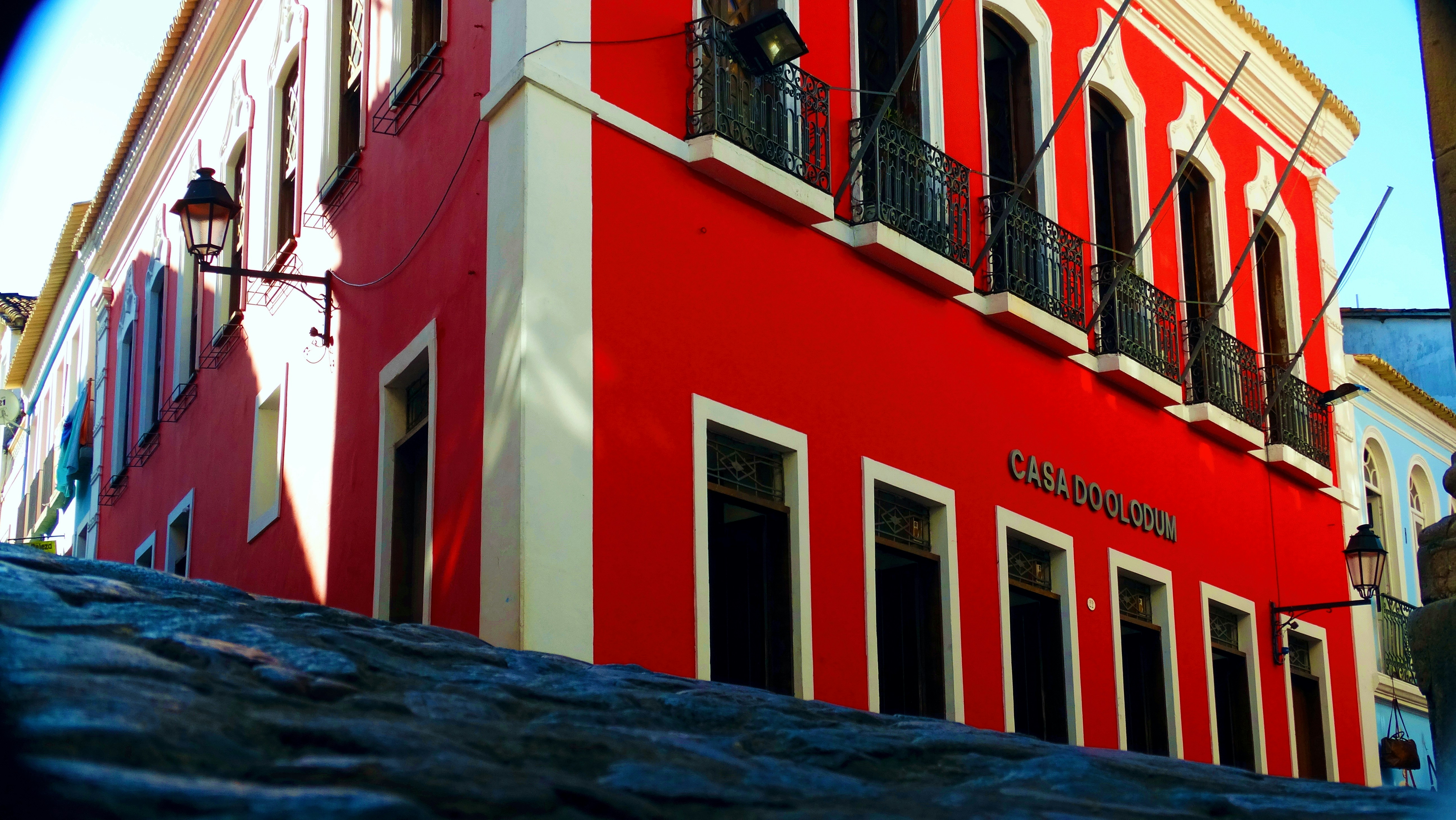 Red and white building with wrought iron balconies under a clear blue sky.
