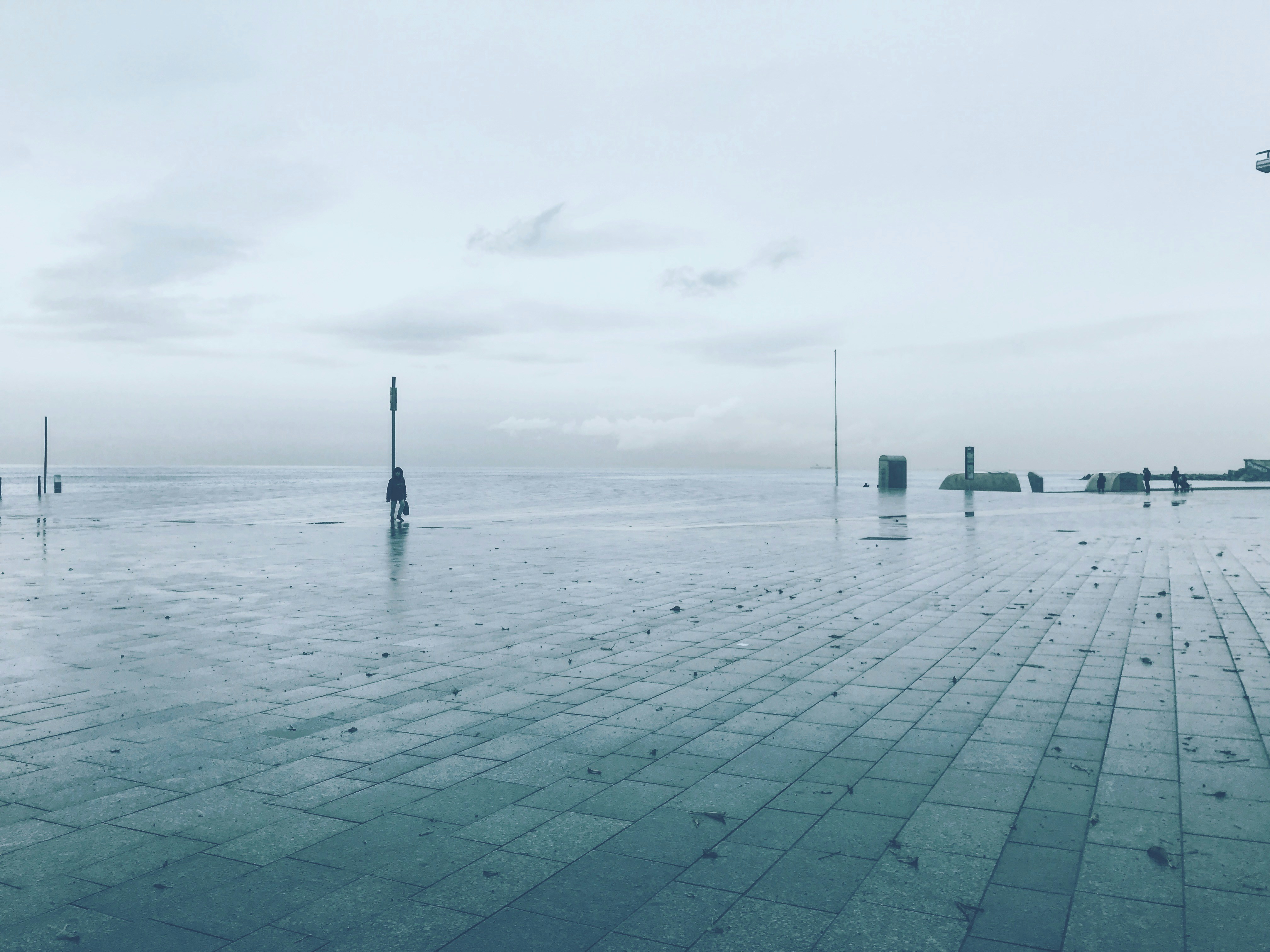 Lone Figure on a Slate Quay Under a Cold, Wide Sky