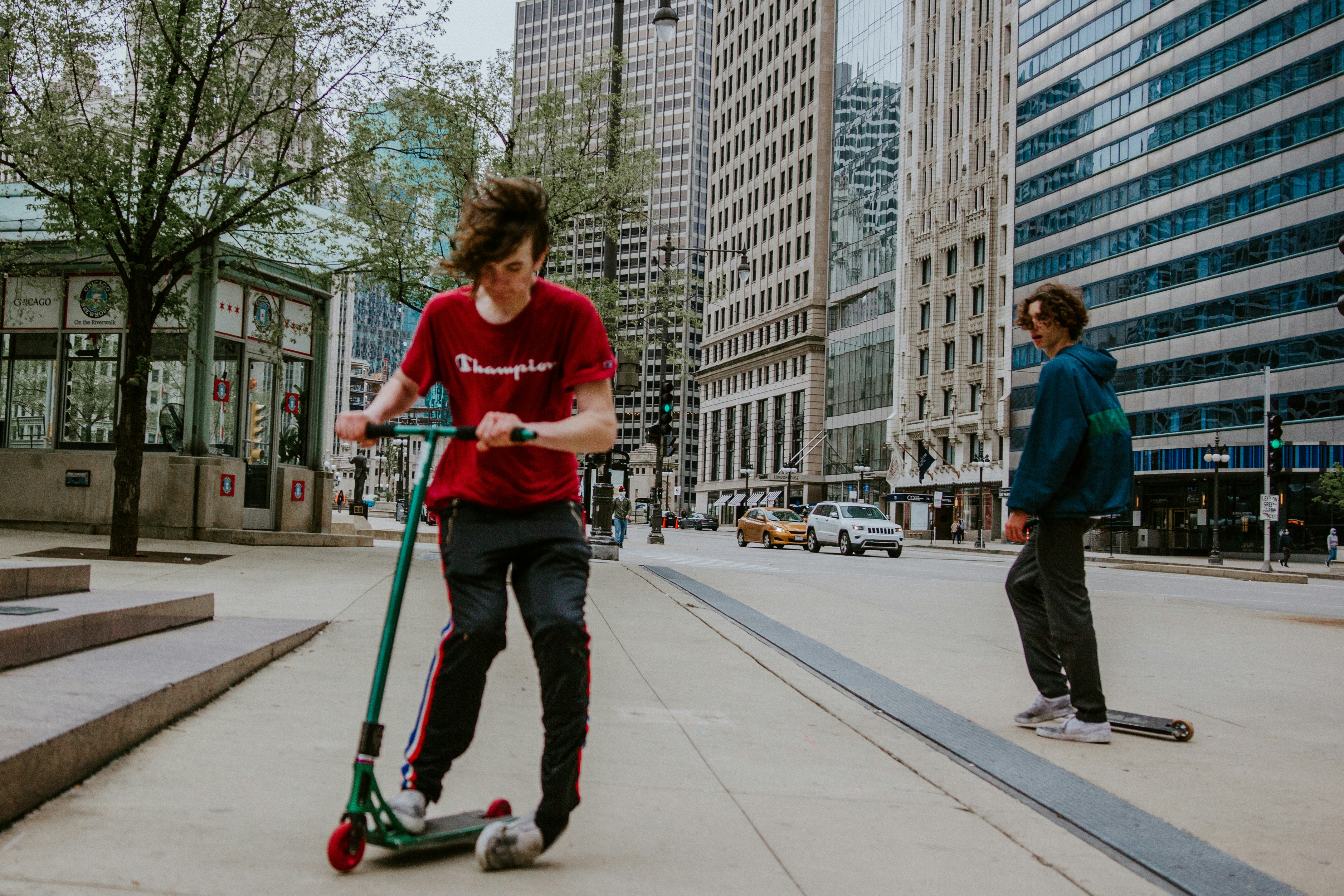 Scarlet Rider on a Green Scooter: City Street Glide Between Skyscrapers
