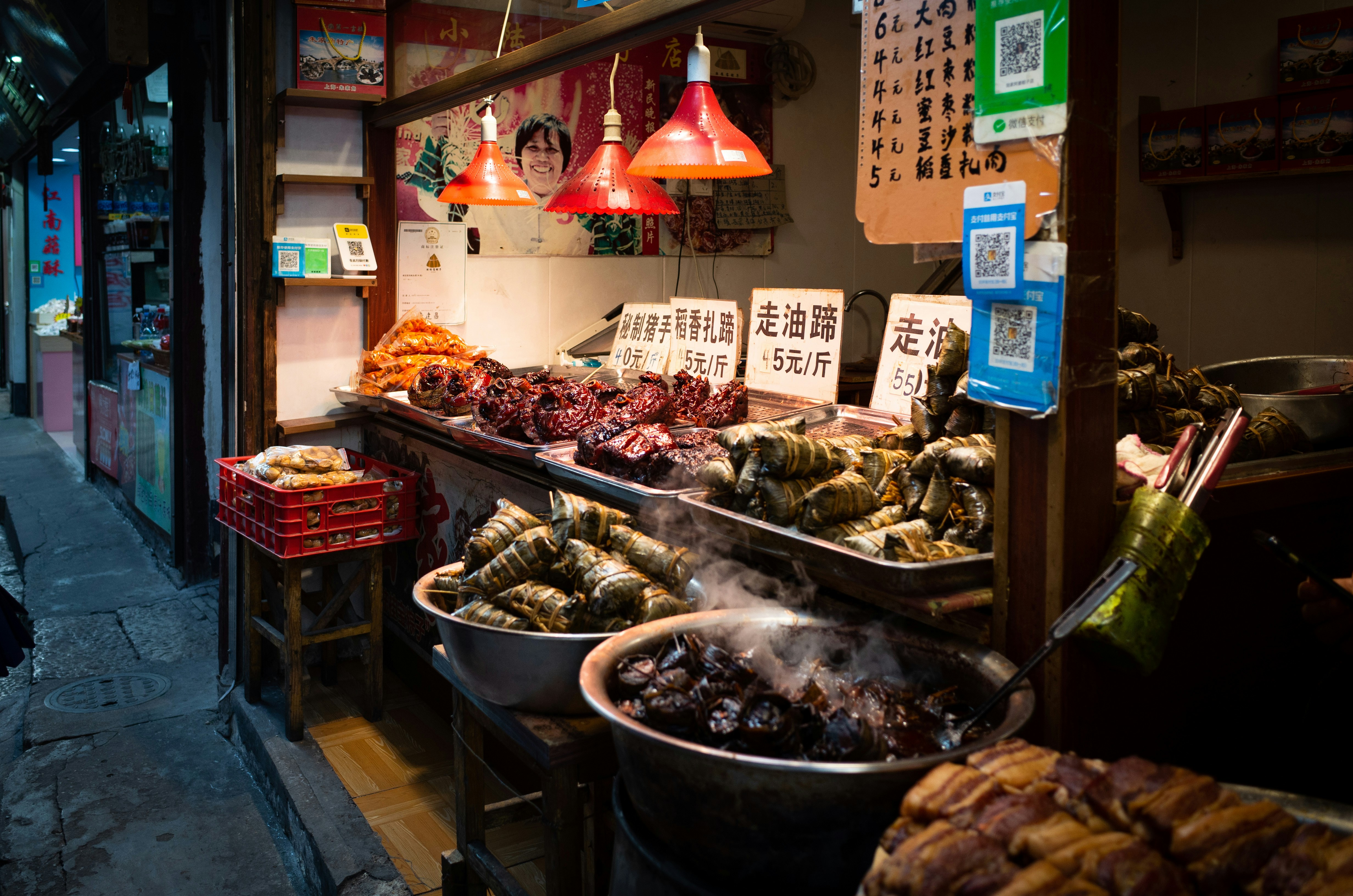 Street food stall displaying steamed buns and wrapped delicacies under warm lighting.