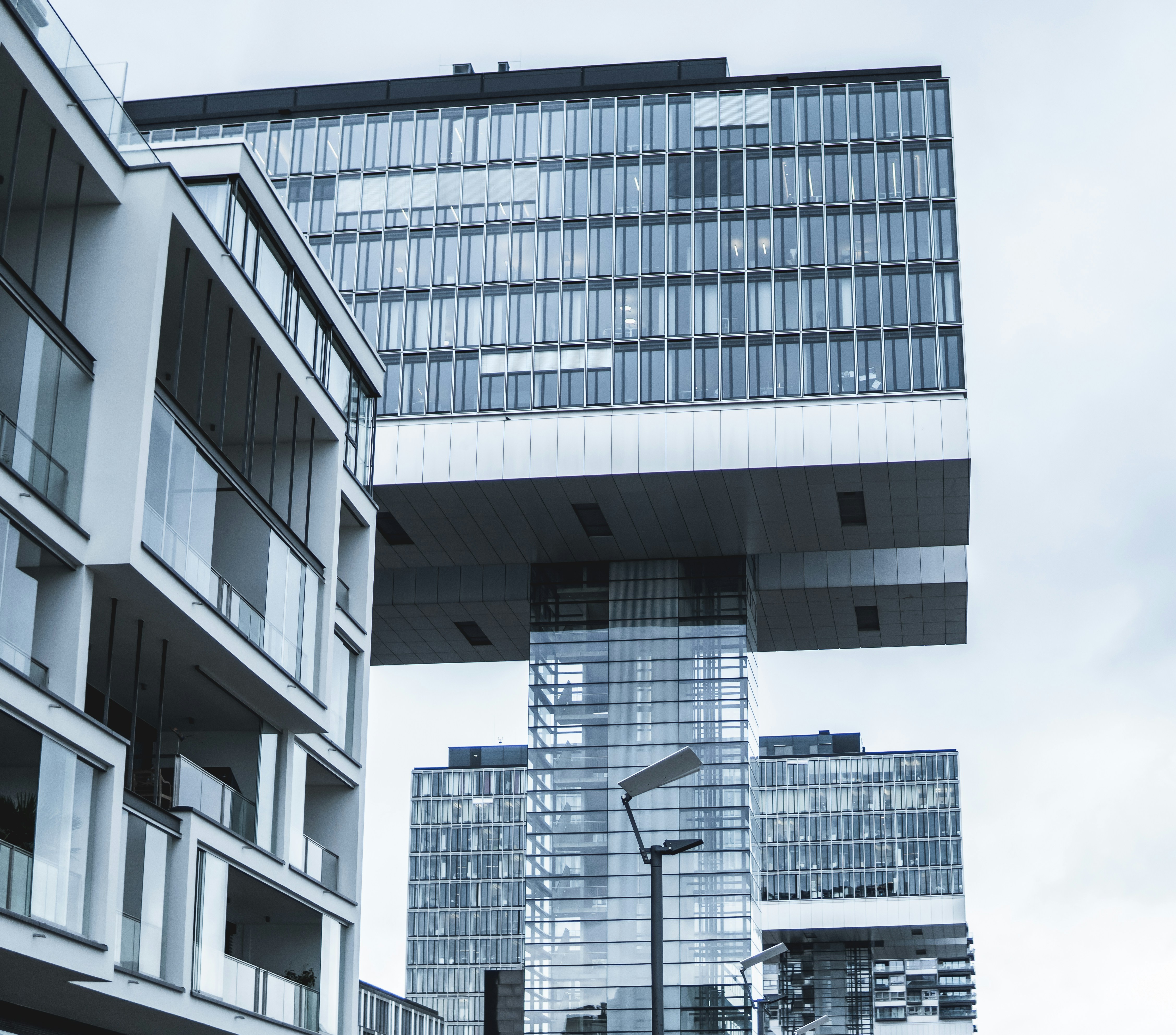Modern architecture of the Kranhäuser buildings with their distinctive crane-like structure set against a cloudy sky.