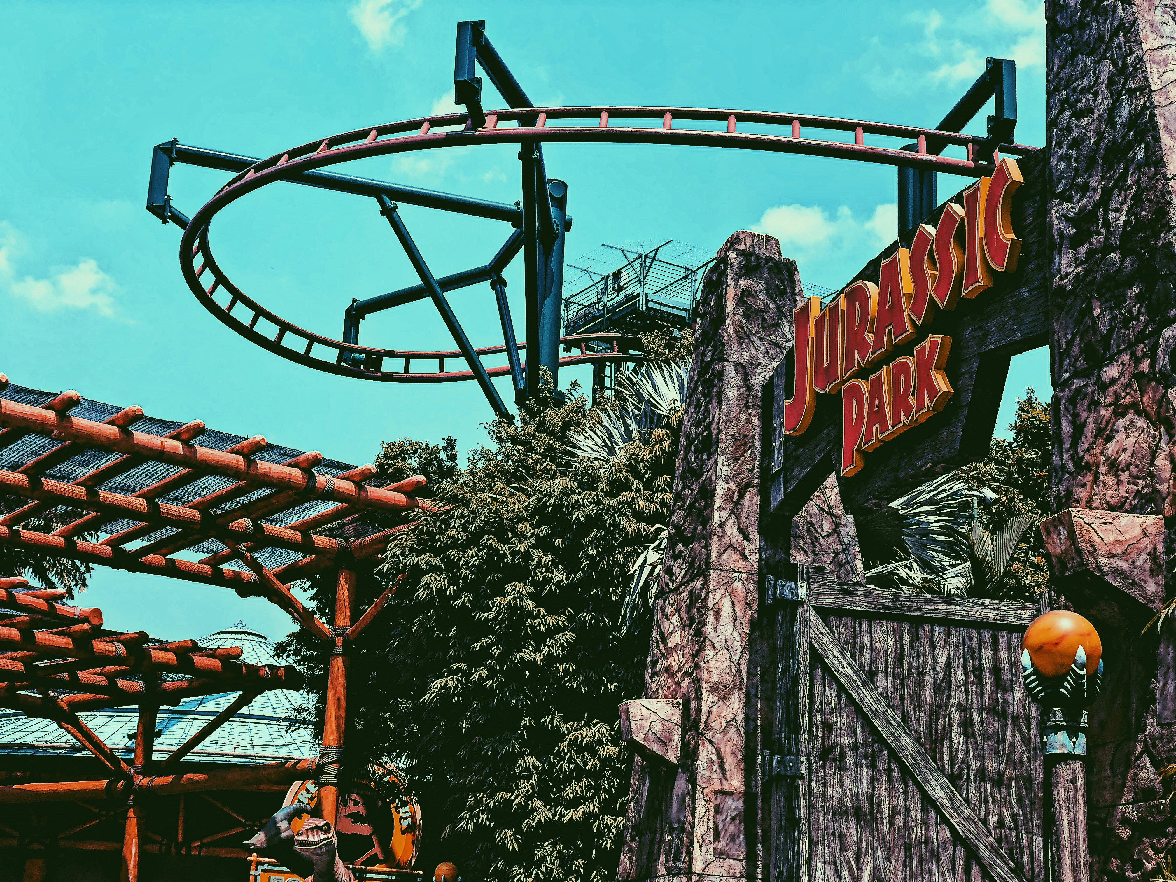 a sign for a park with a roller coaster in the background