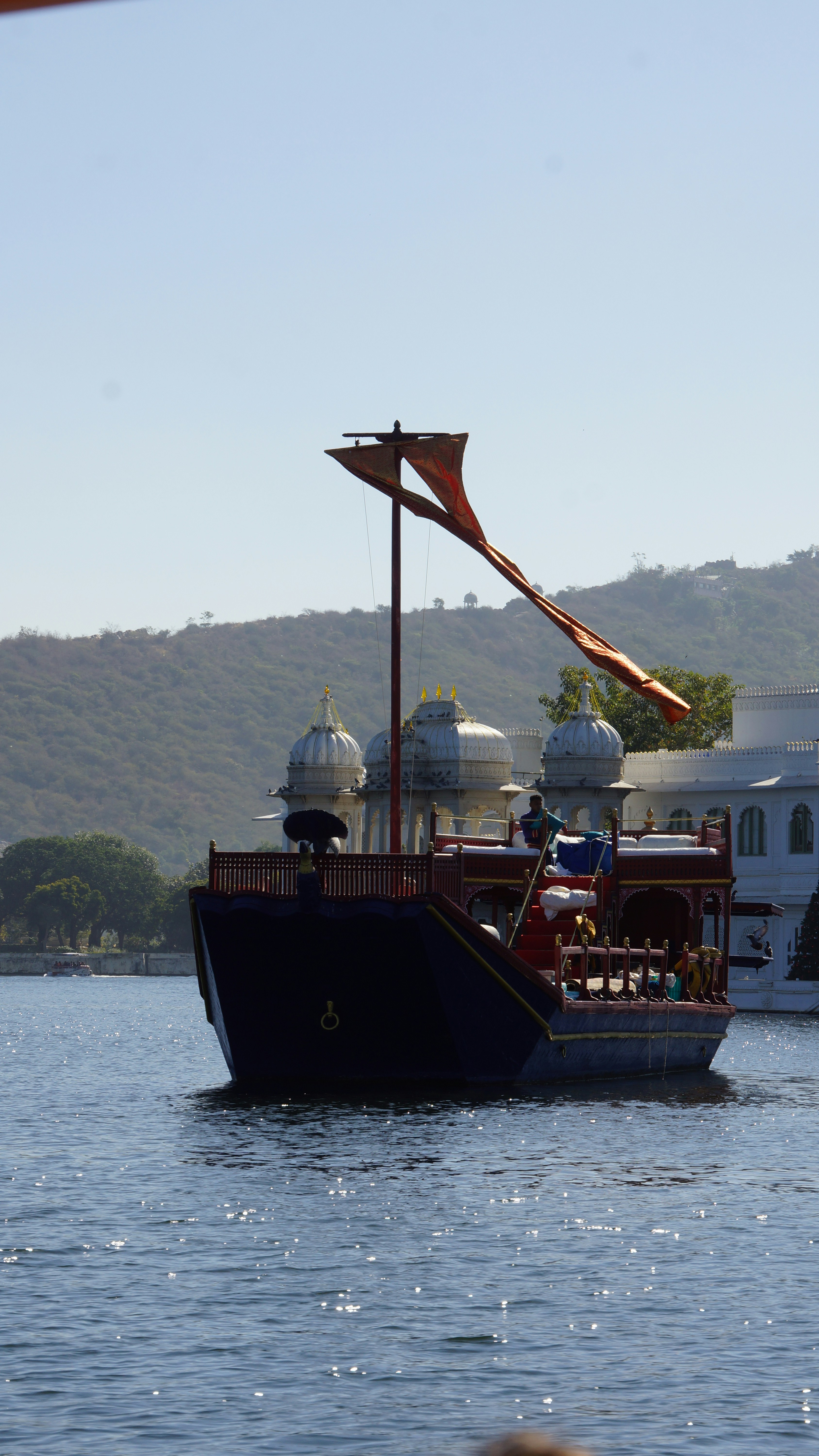 Flagged Vessel: A ceremonial boat gliding beside a temple complex